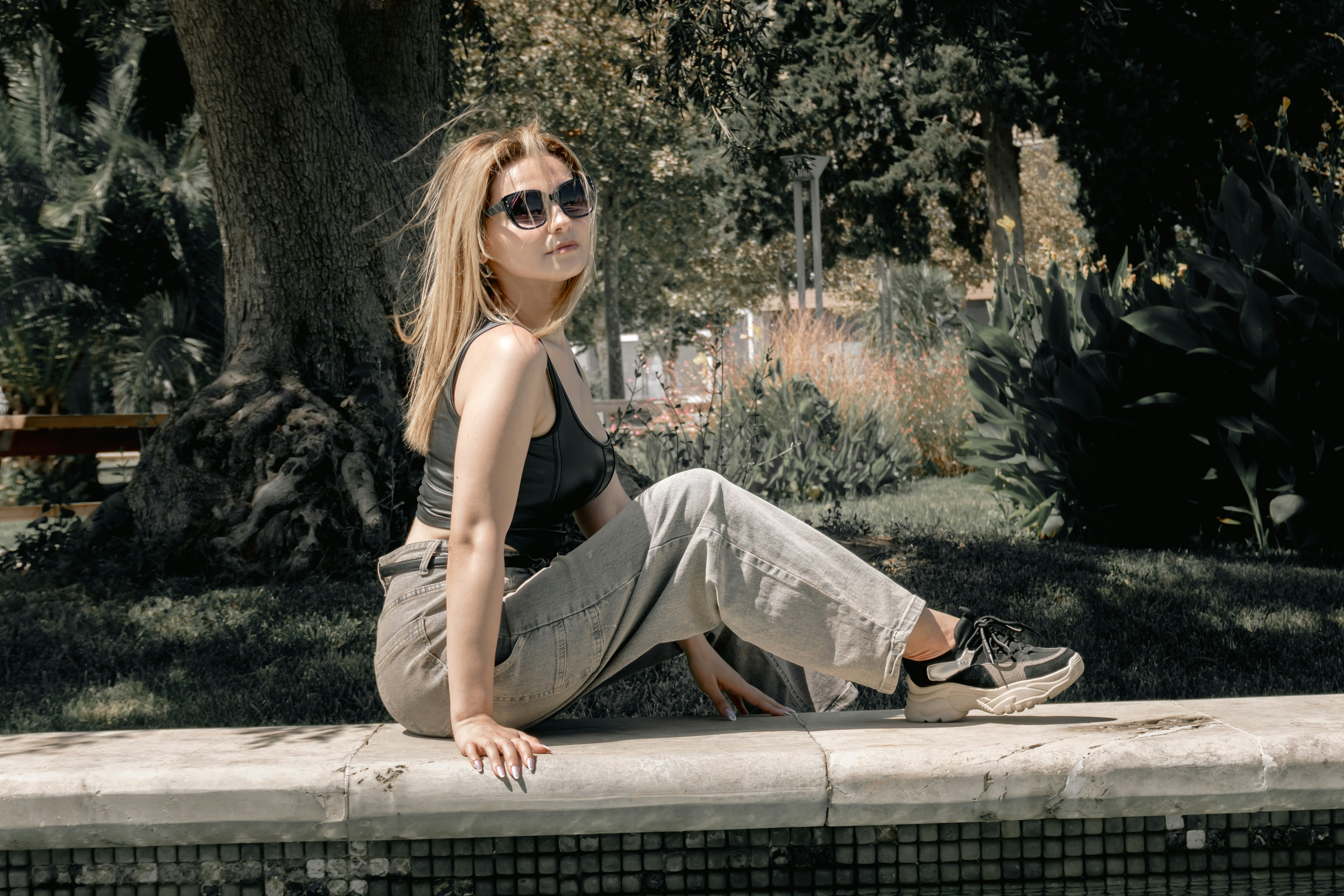 Sunlit Leisure: A Woman in Sunglasses Seated by a Poolside