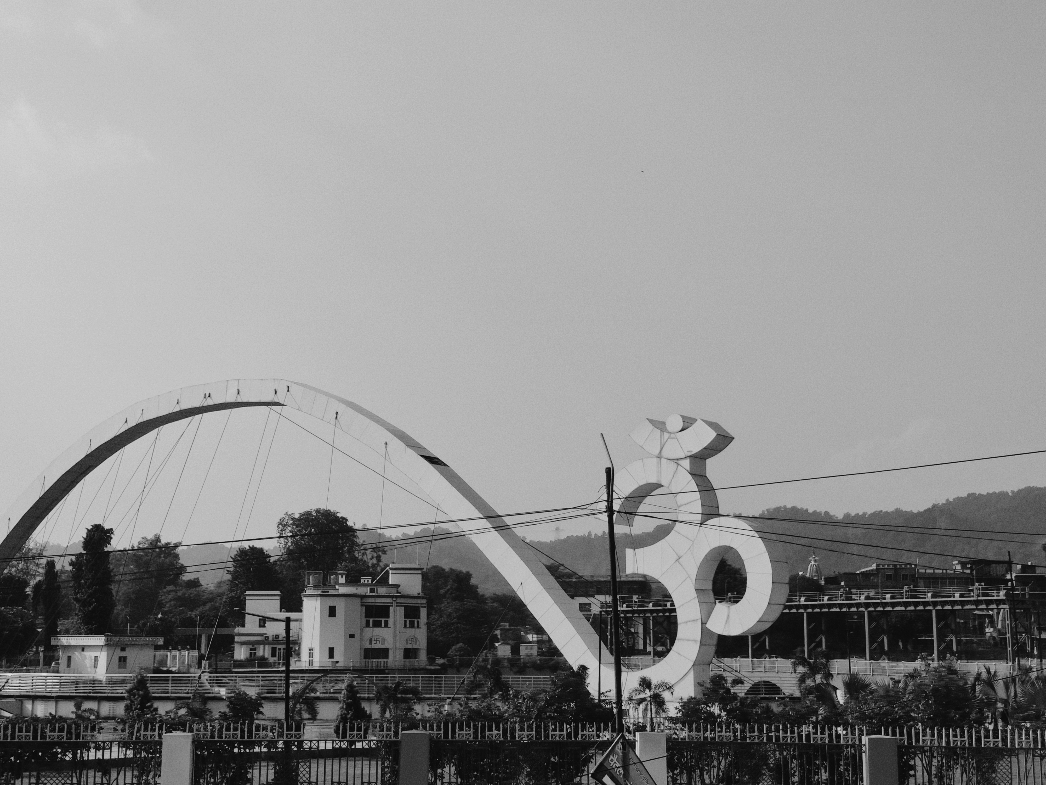 Monochrome skyline: a curved bridge and sculptural monument over a quiet riverside