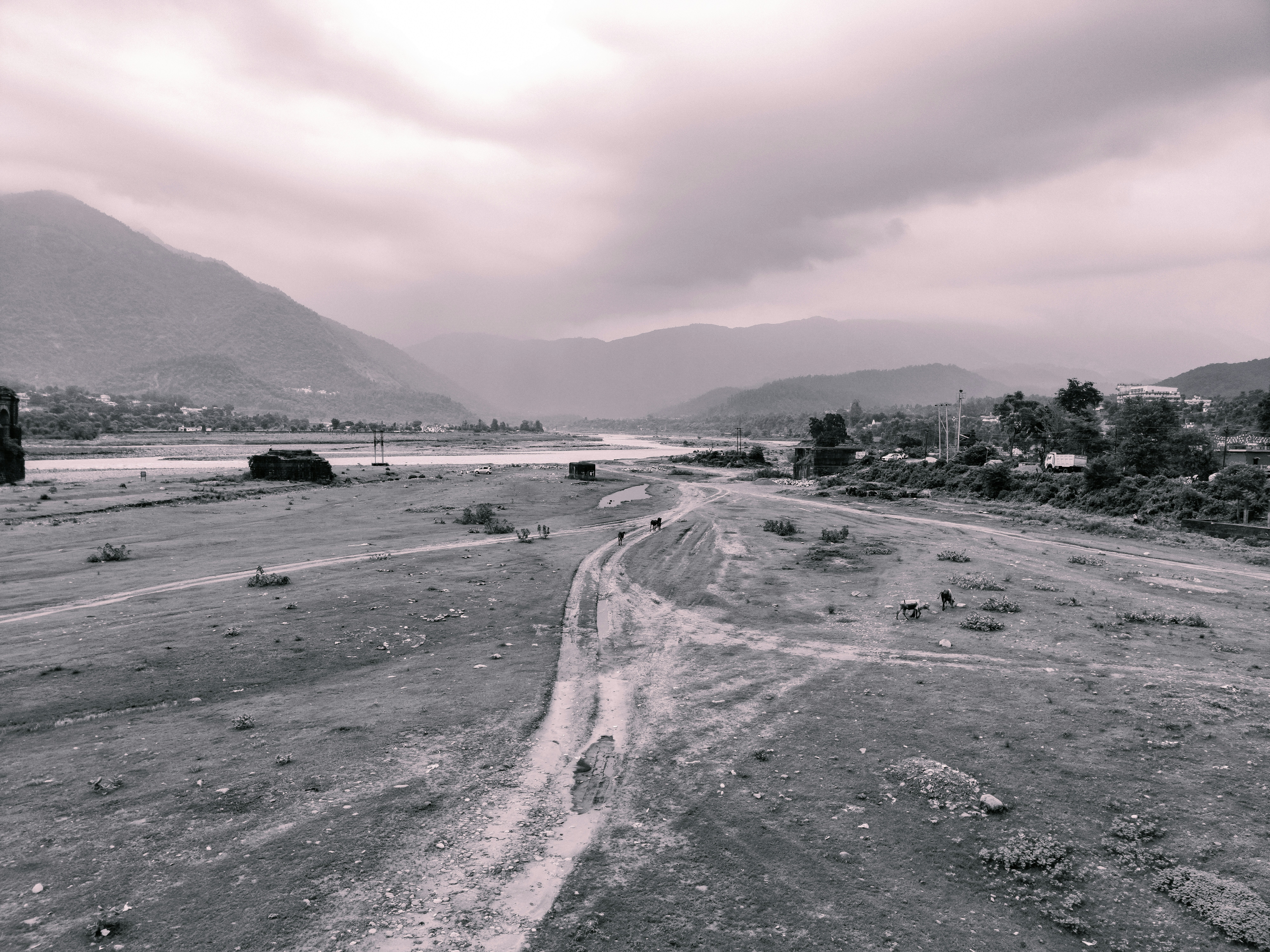 Dusty riverbed winds toward distant hills under a moody sky