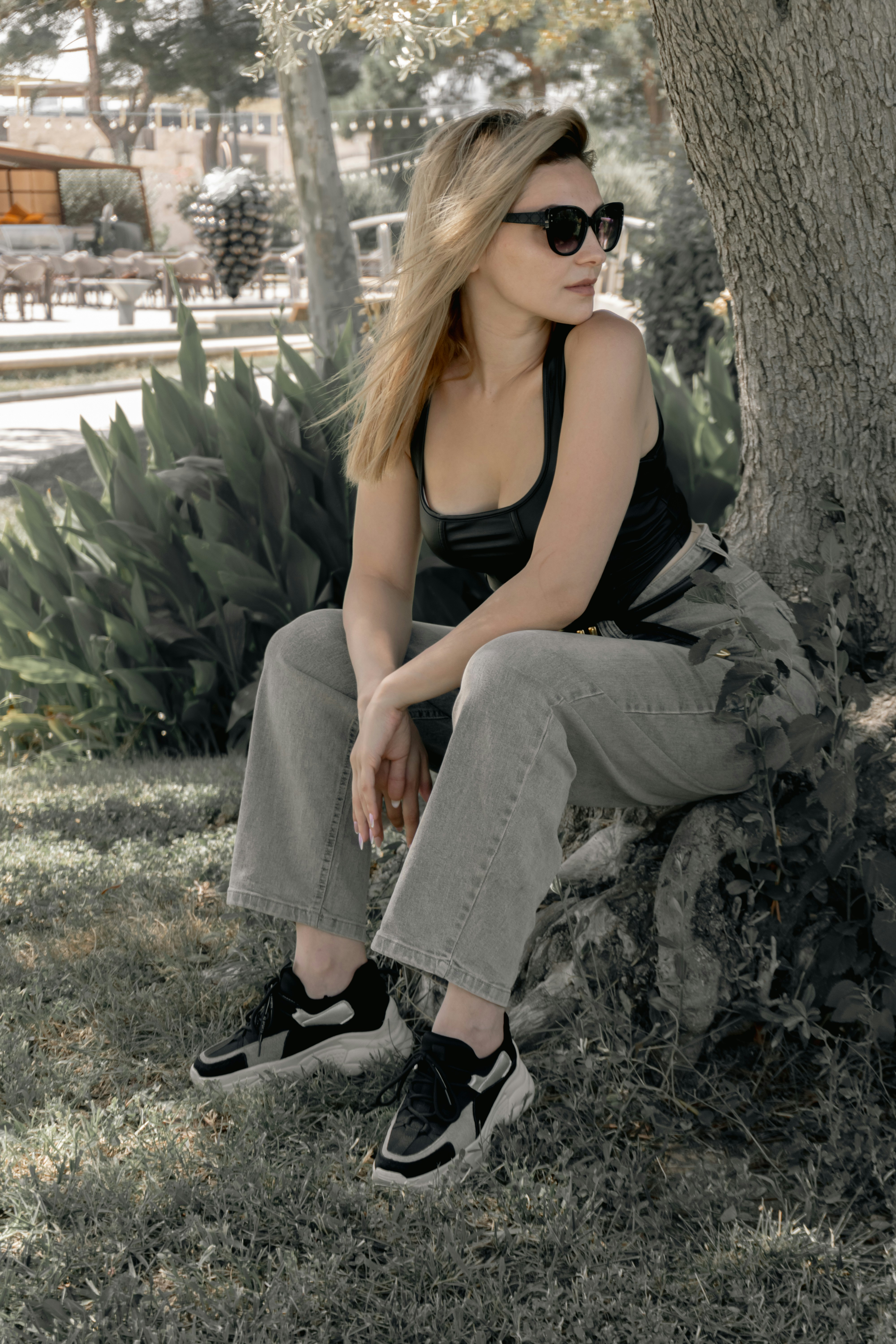 Shaded Confidence: A Woman in Sunglasses by the Tree