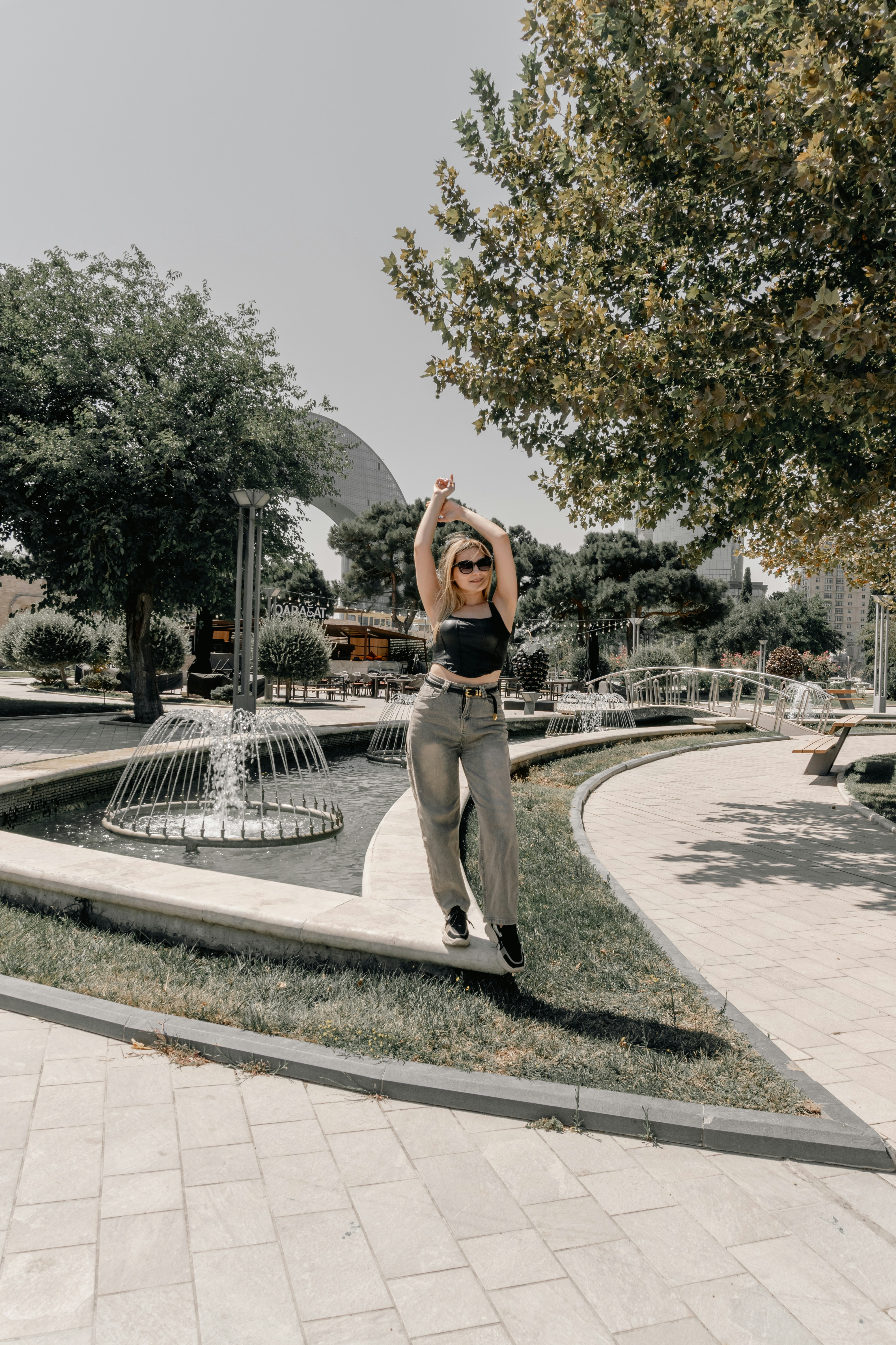 Solo dancer on a sunlit park path framed by fountains and trees