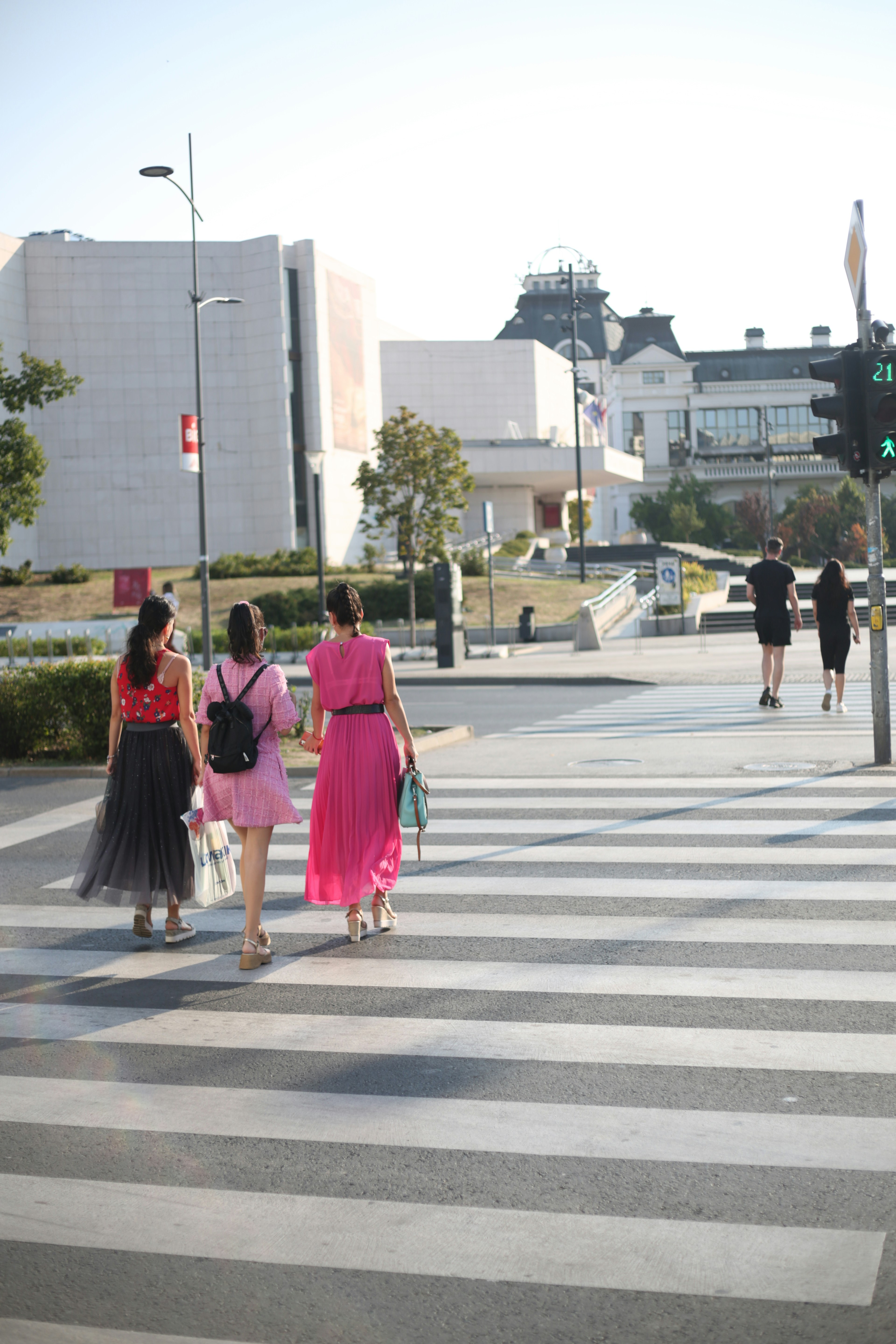 Three Walkers in Coordinated Evening Hues Crossing an Urban Crosswalk