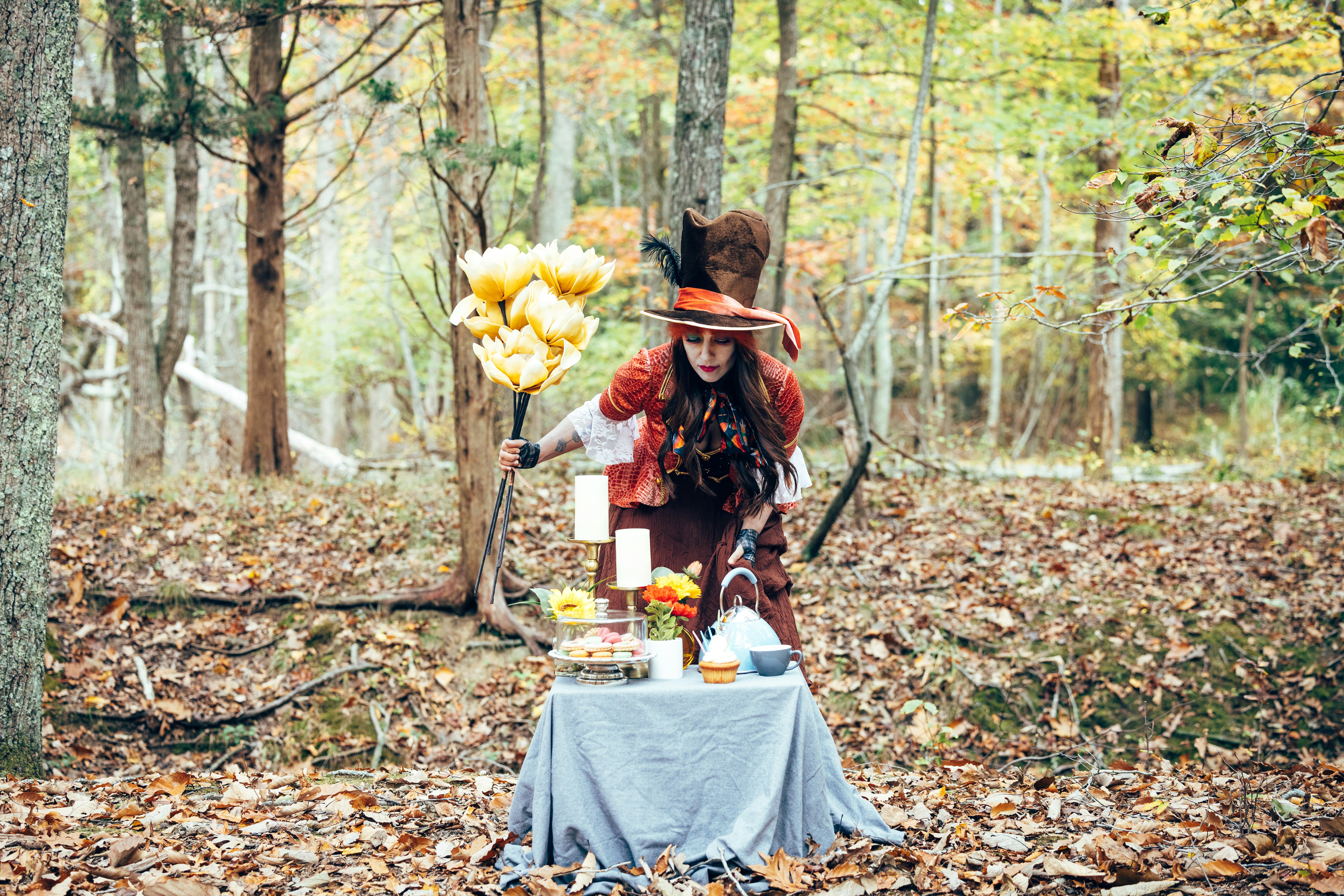Mad hatter character in forest with small tea party