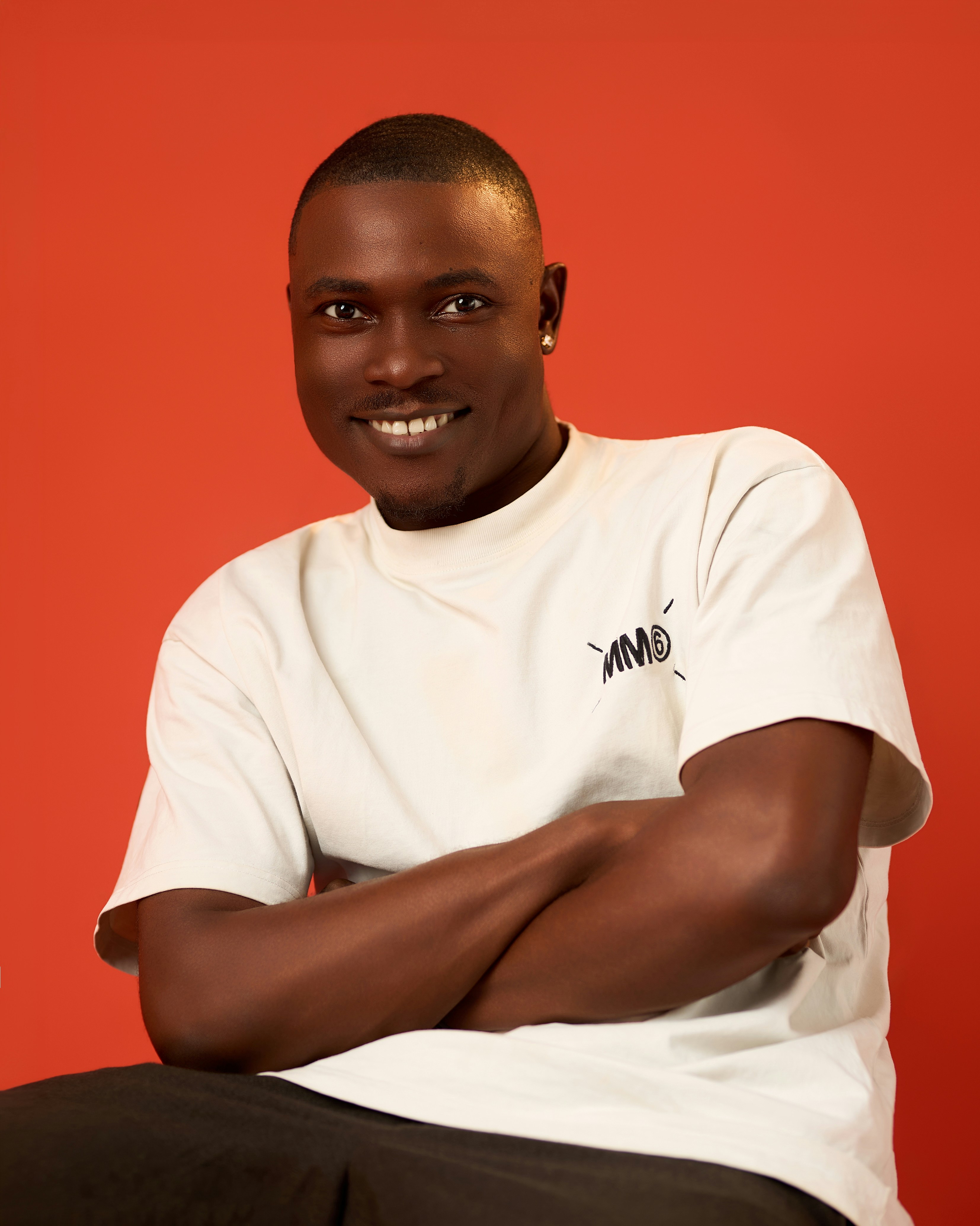 Confident grin on a warm orange backdrop