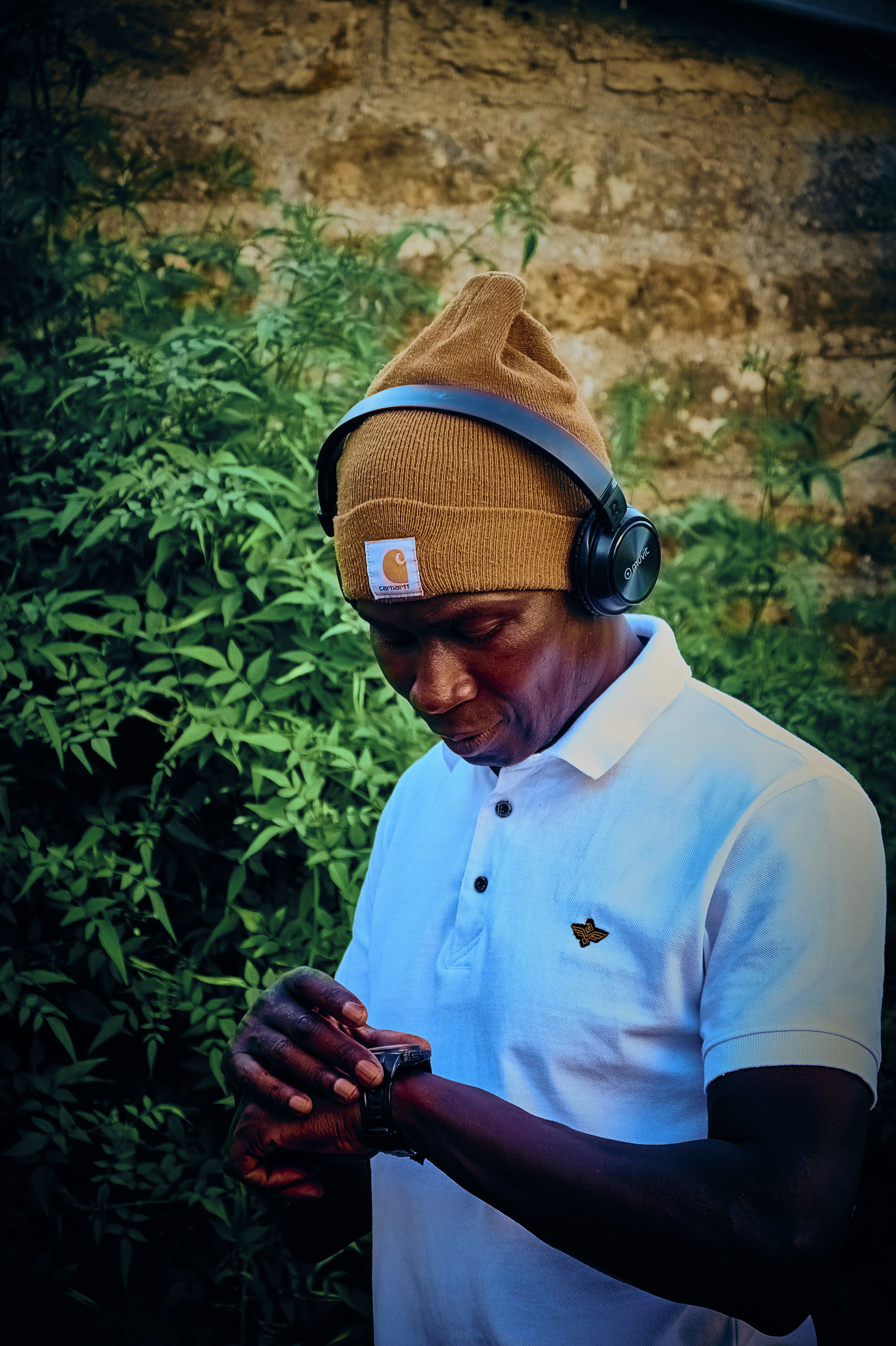 Focused Moment: a man in a white polo listening with headphones while checking his watch