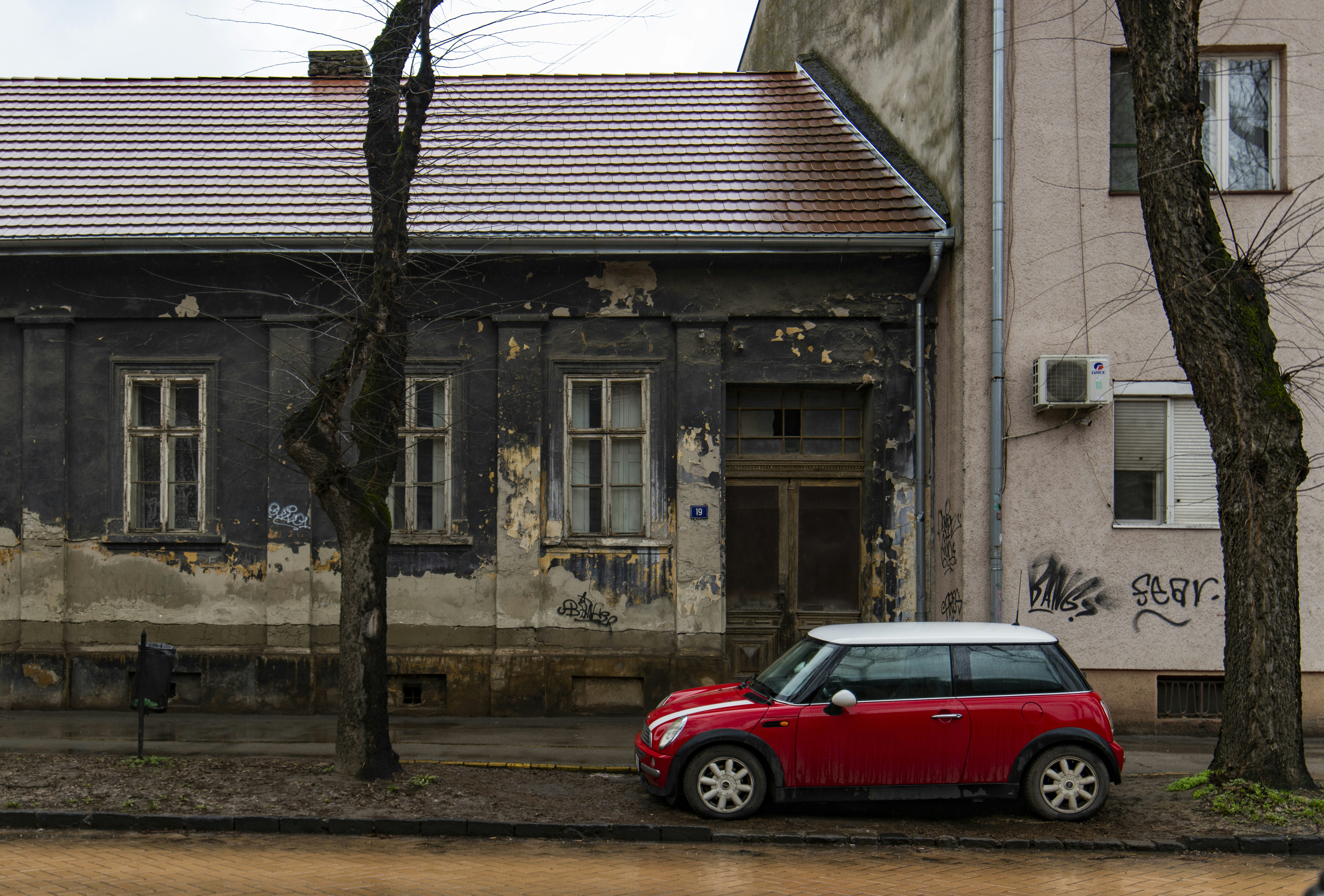 Red Hatchback in Front of Weathered Facade
