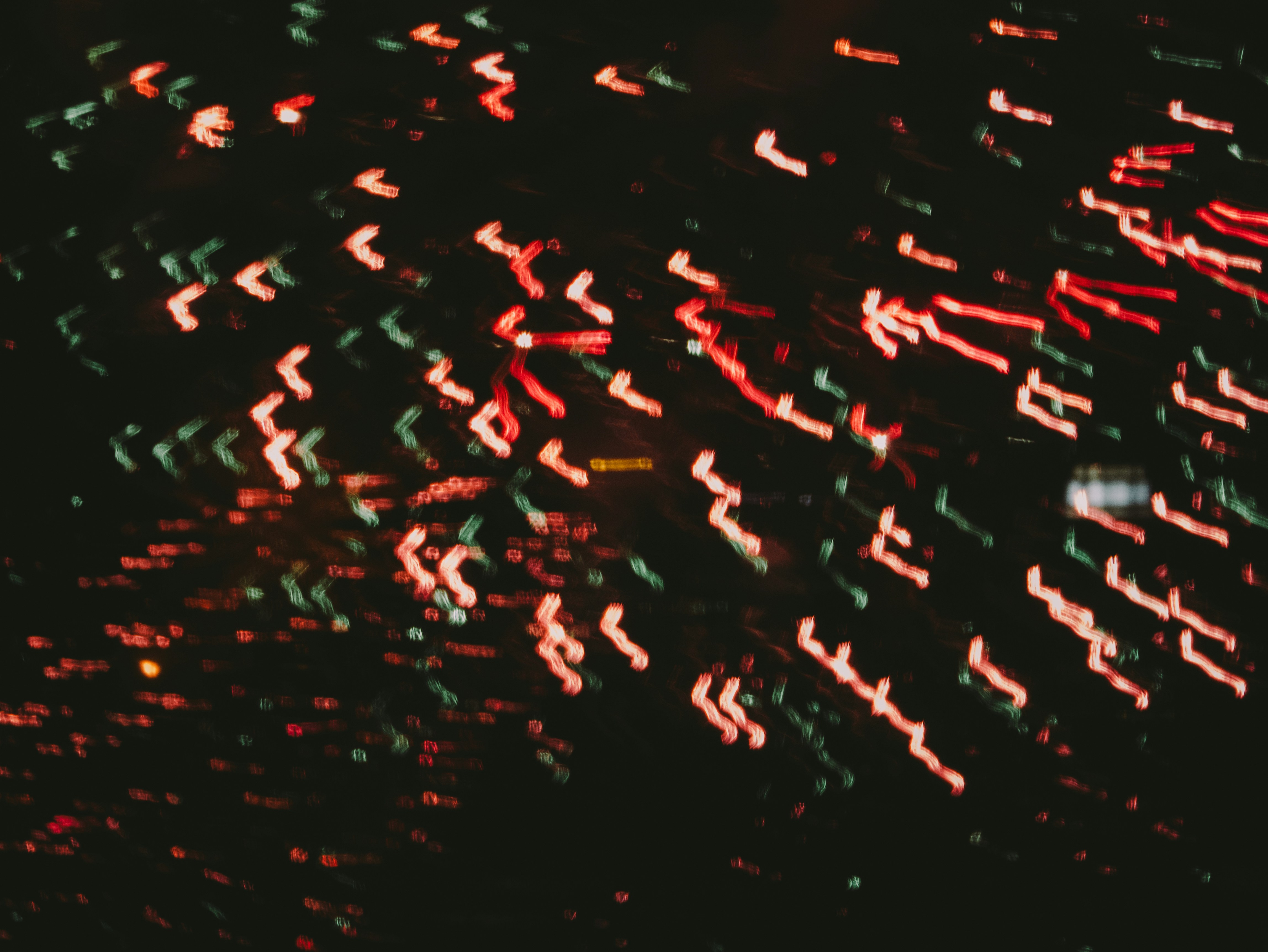 Abstract night lights streak like neon rain across a dark frame, conveying motion and energy in a cityscape. The image captures colorful bokeh paths with a moody, nocturnal atmosphere.