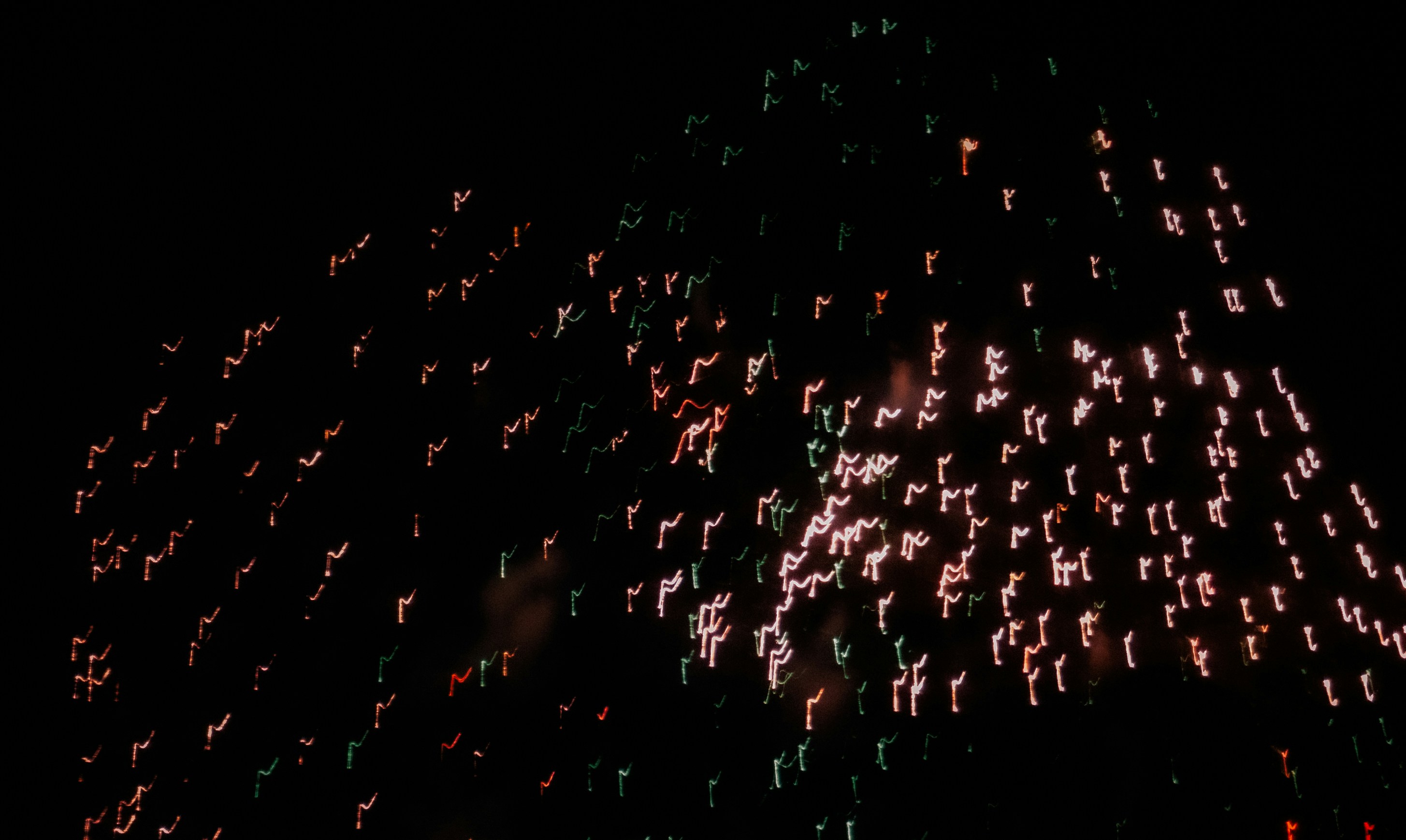 Abstract night scene with numerous small, glowing bokeh lights scattered across a dark background, suggesting suspended embers or distant lanterns. A minimal, moody composition focusing on light and movement.