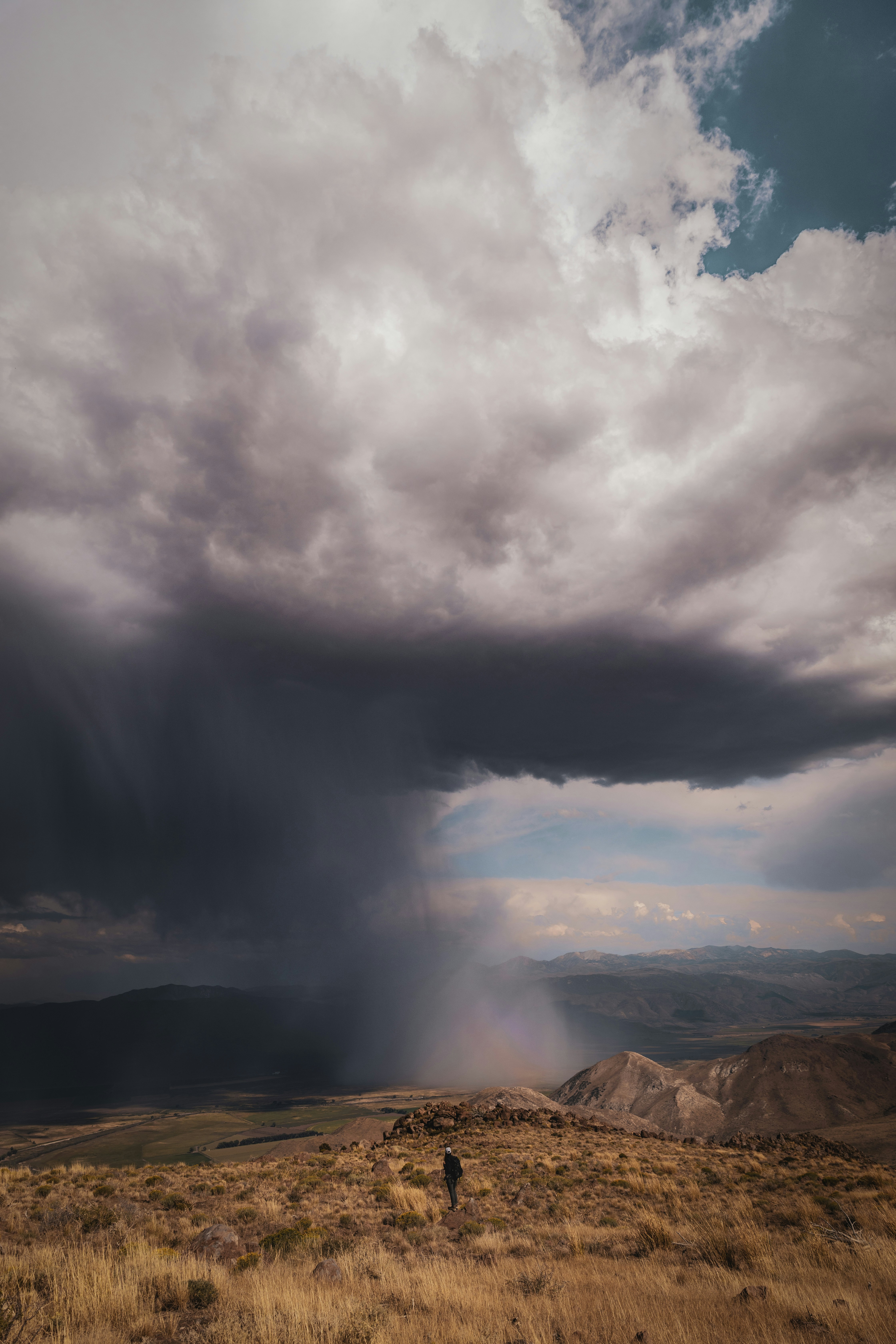 Solo Figure Beneath a Looming Storm on a Rugged Hill