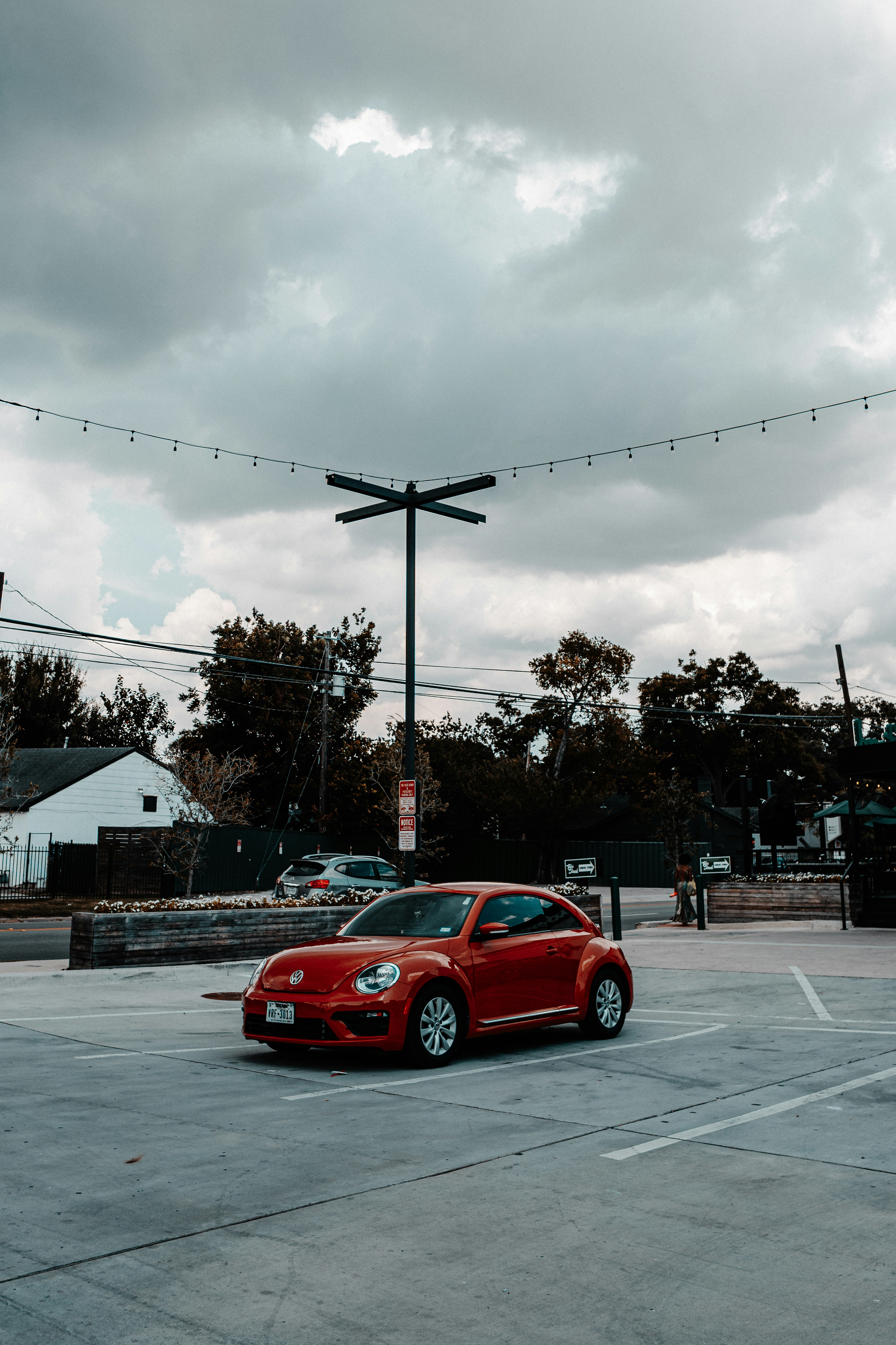 Red VW Beetle in a Quiet Parking Lot Under a Stormy Sky