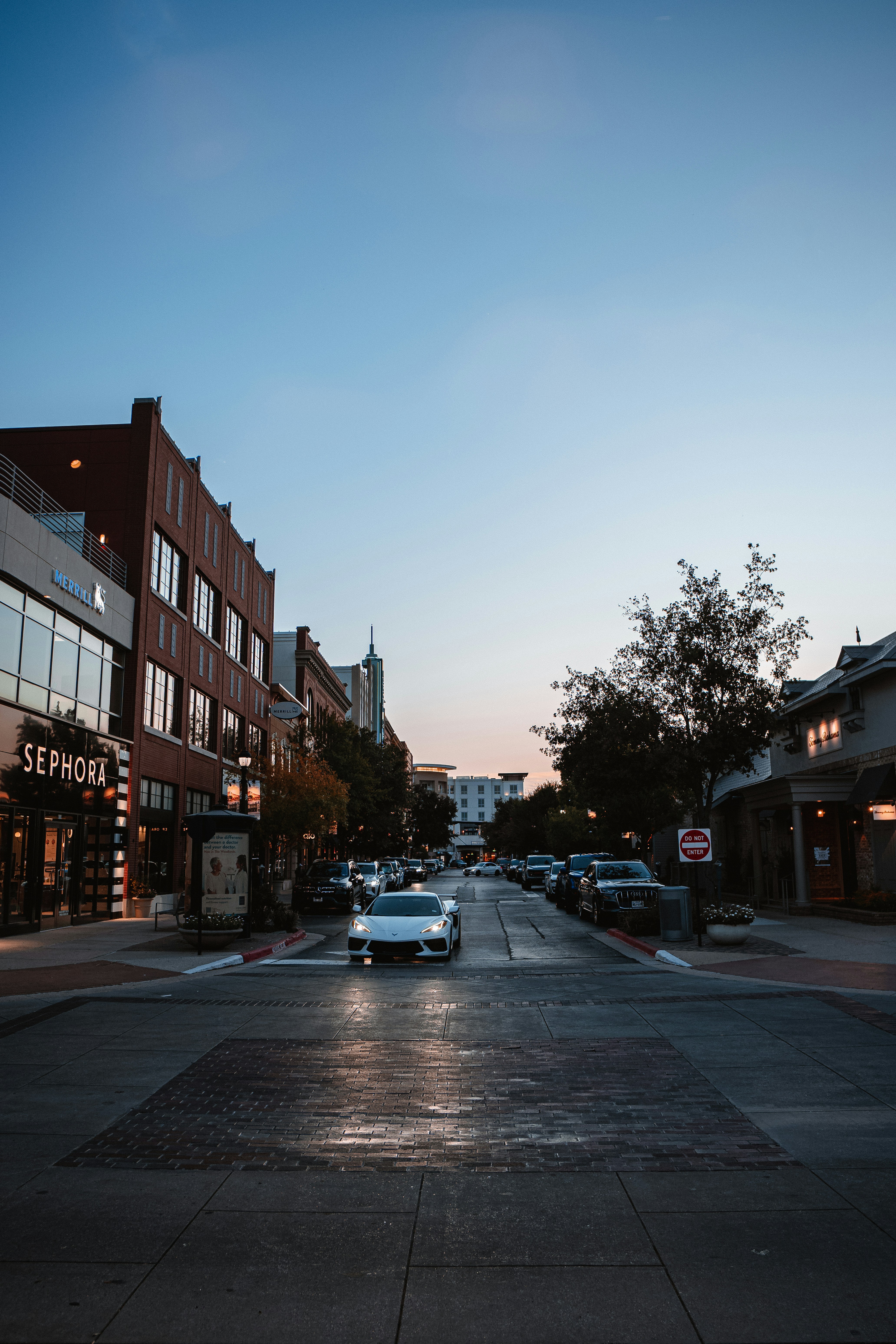 City Street Vista at Dusk: Shops, Traffic, and Quiet Skies