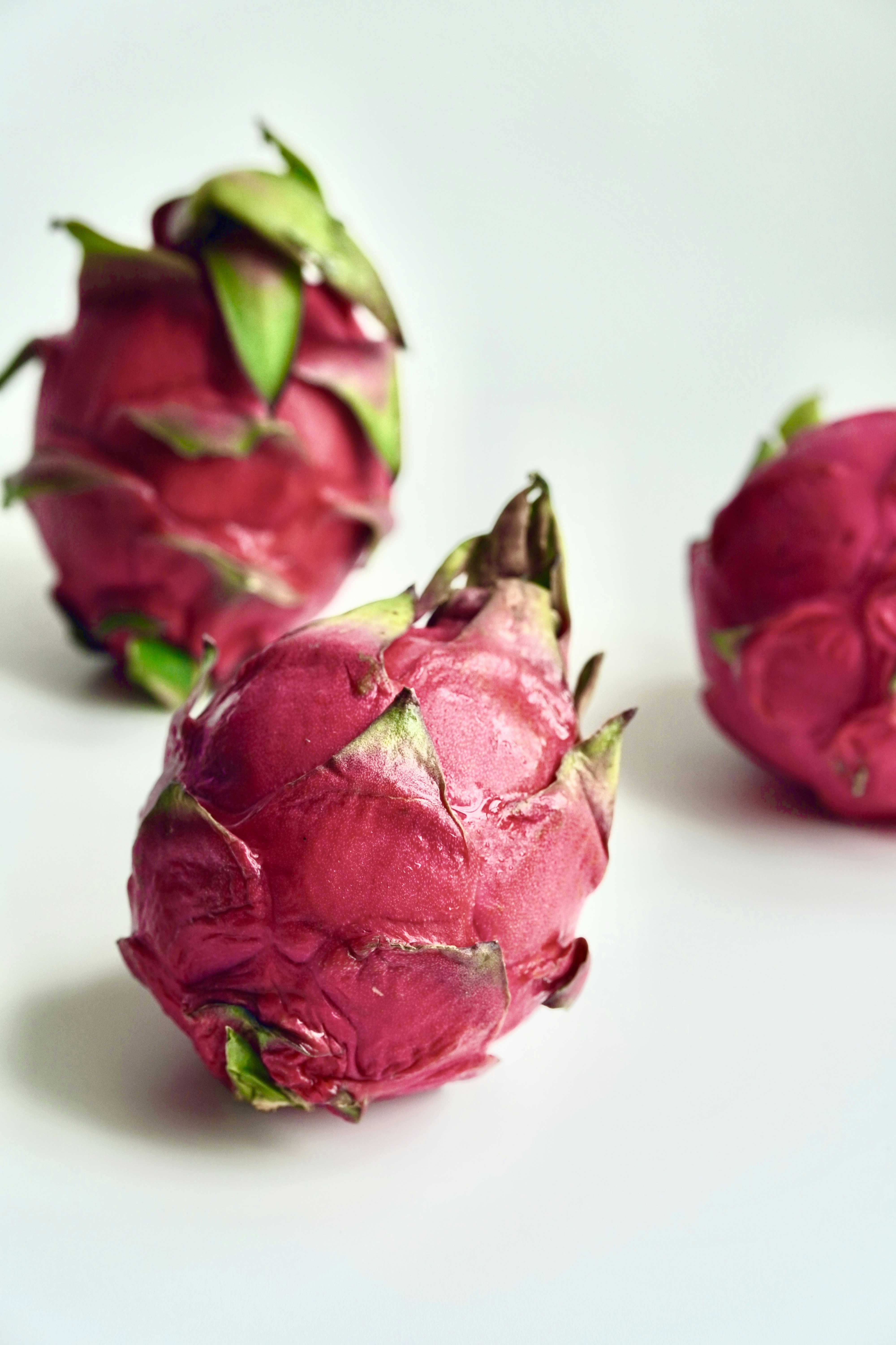 Three vibrant pink dragon fruits on a white background.