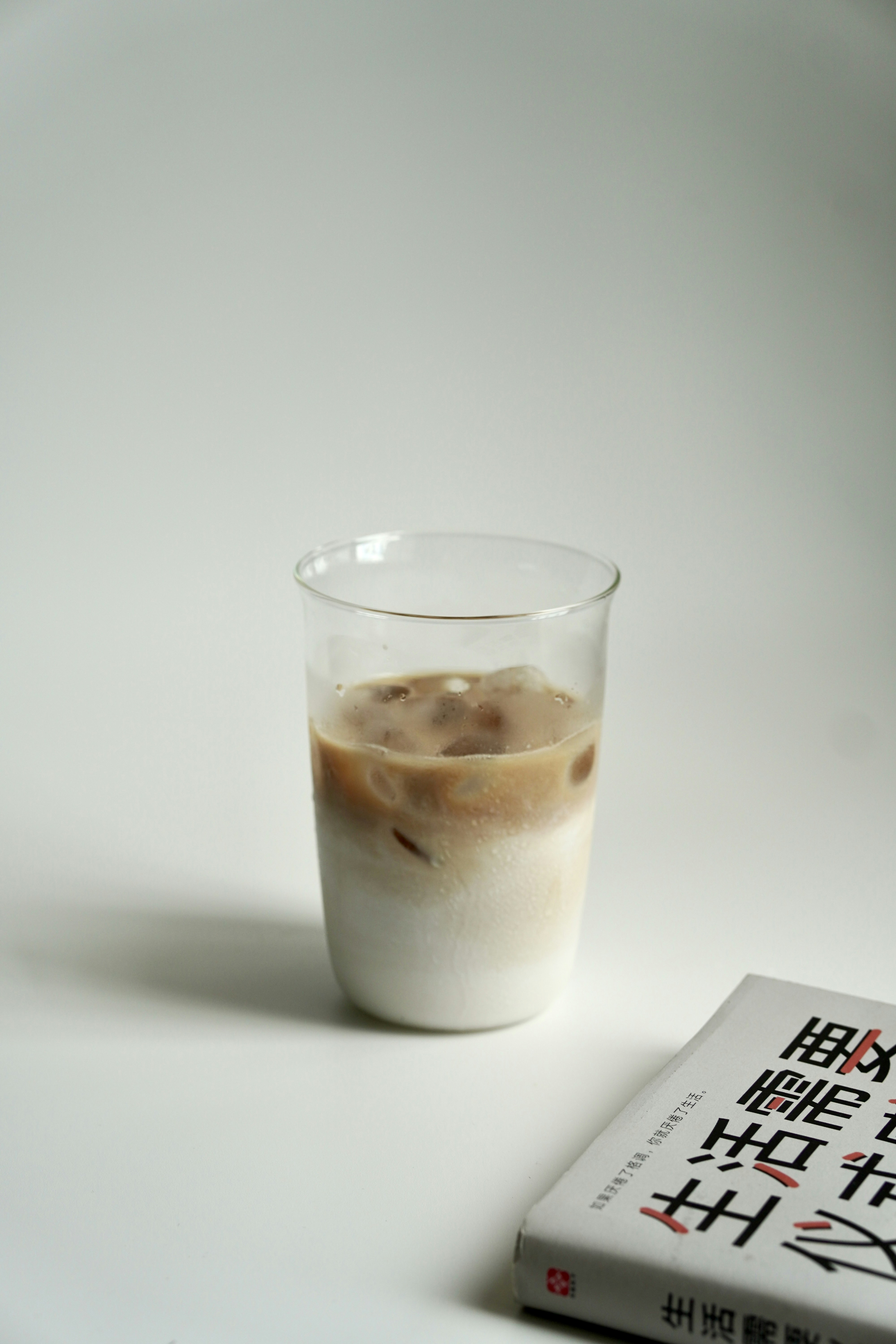 Layered iced coffee in a glass against a minimalist white backdrop