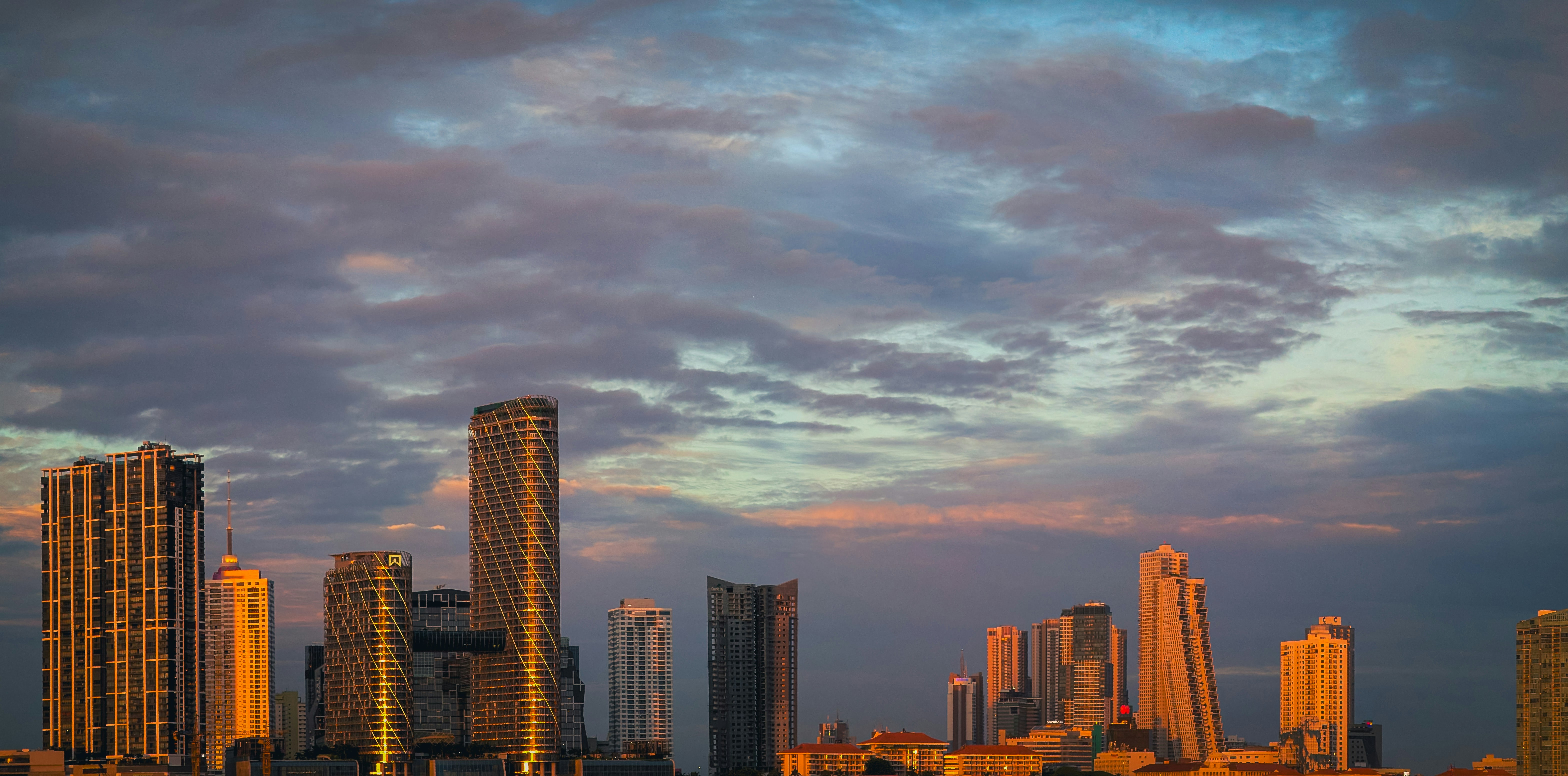 Modern city skyline at sunset with cloudy sky.