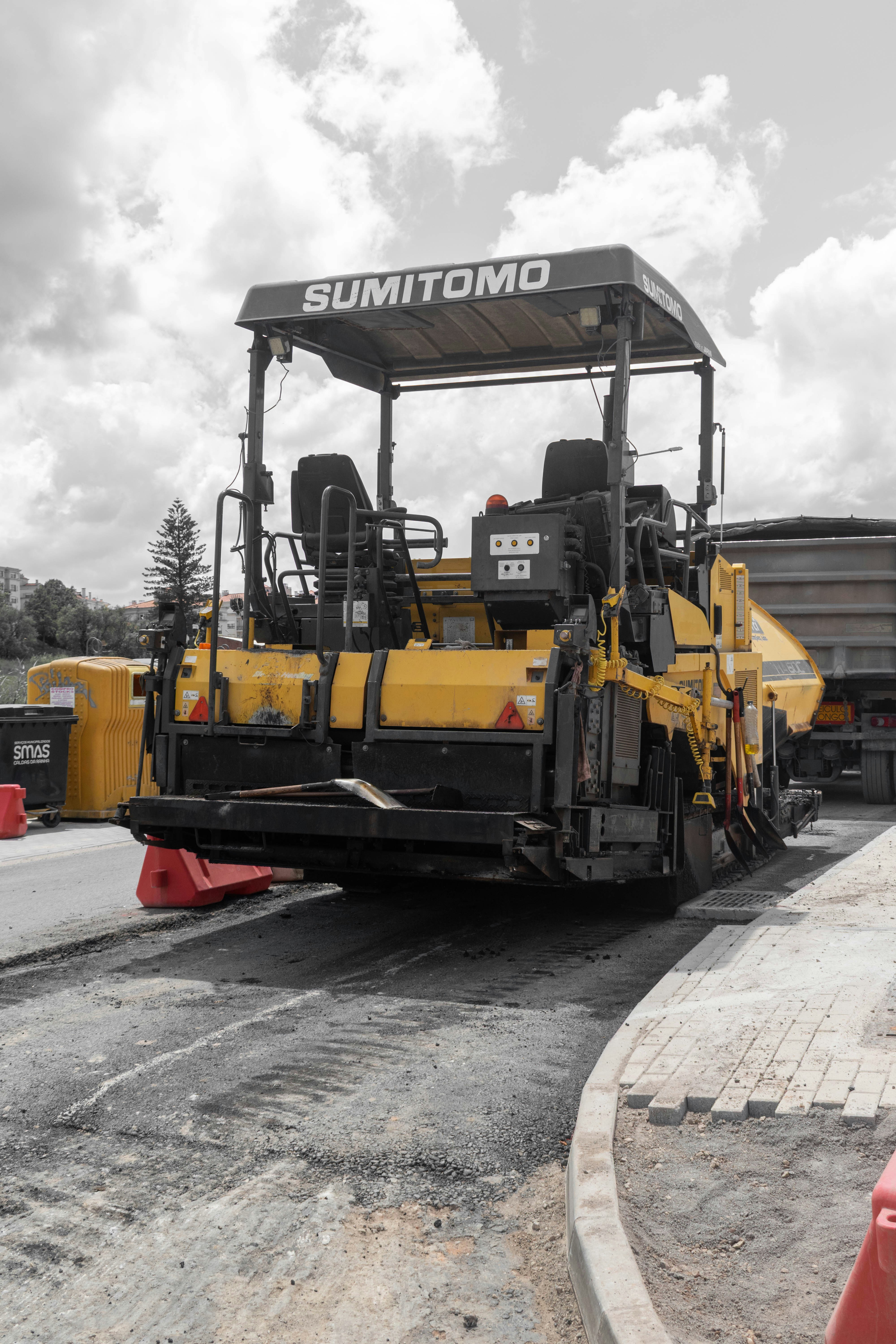Sumitomo Road Roller at Work: Yellow Machinery amid Fresh Asphalt