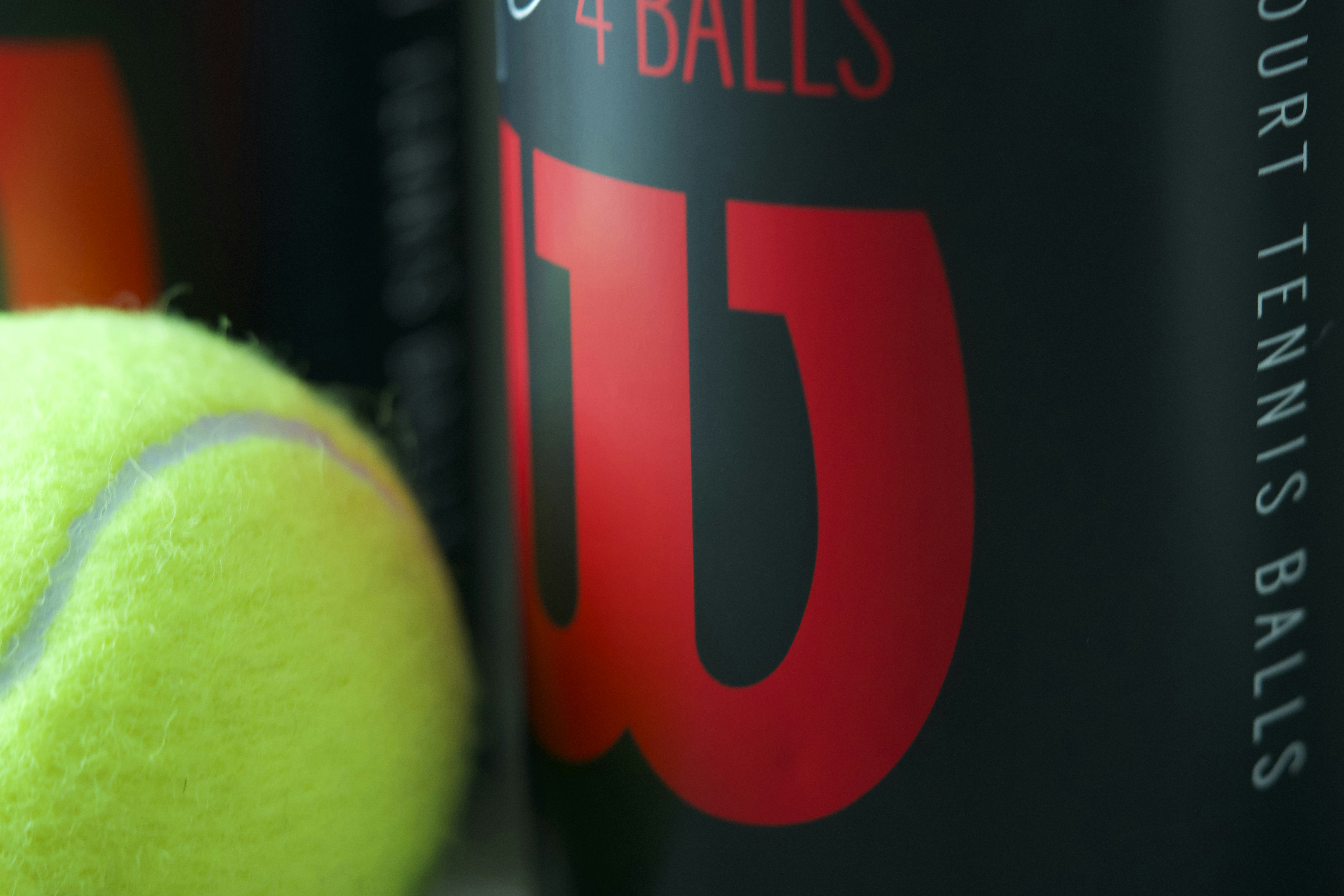Close-up of a neon-red bottle label beside a tennis ball