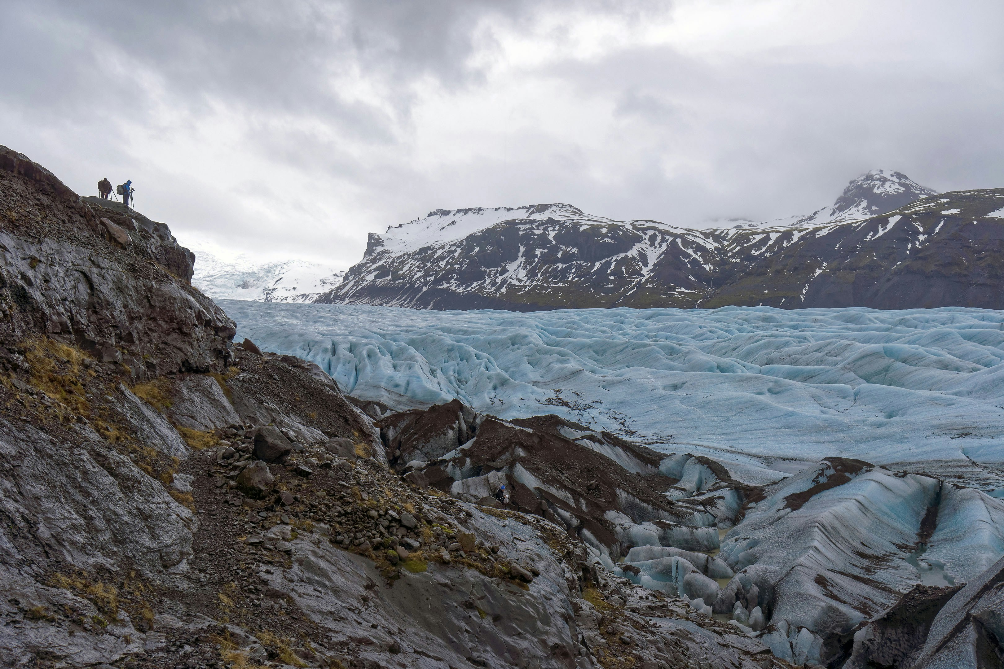 Glacial Edge at Dusk: Two Climbers Above a Blue Icefield