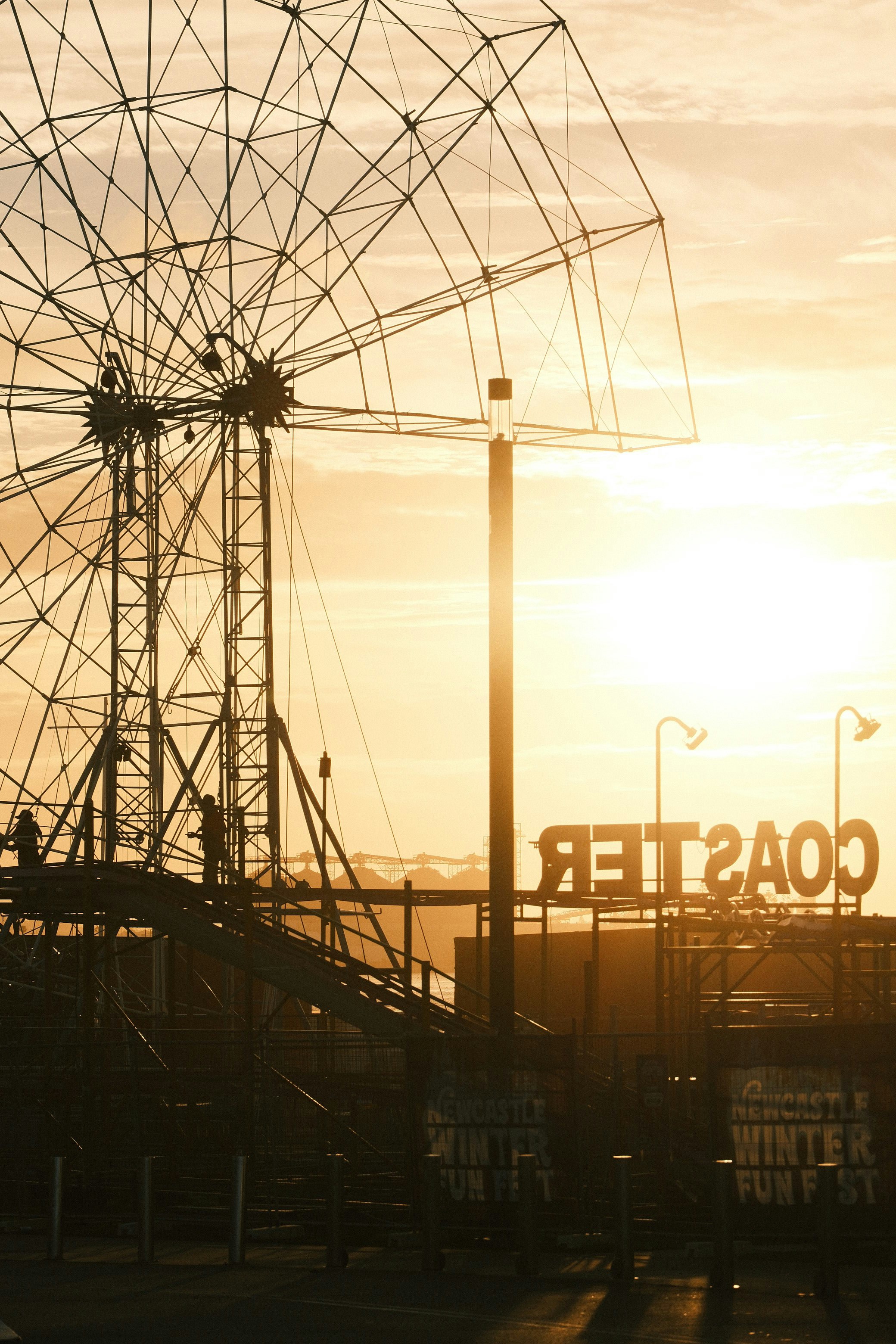 Industrial radio antenna and sign silhouettes bathed in golden sunset light, creating a dramatic skyline.