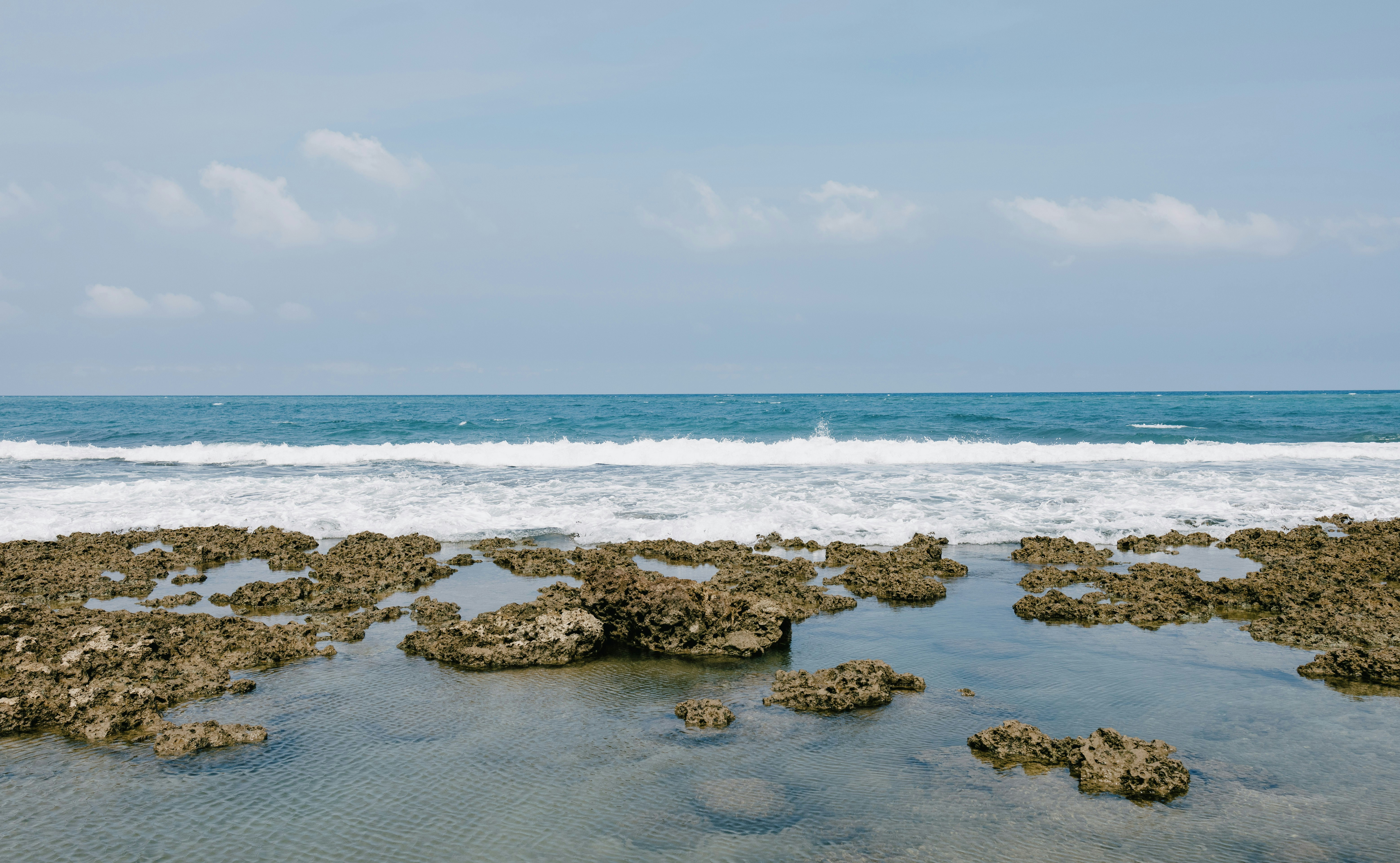 Coastal Glass and Coral: Tide-Washed Rocks Under a Clear Sky
