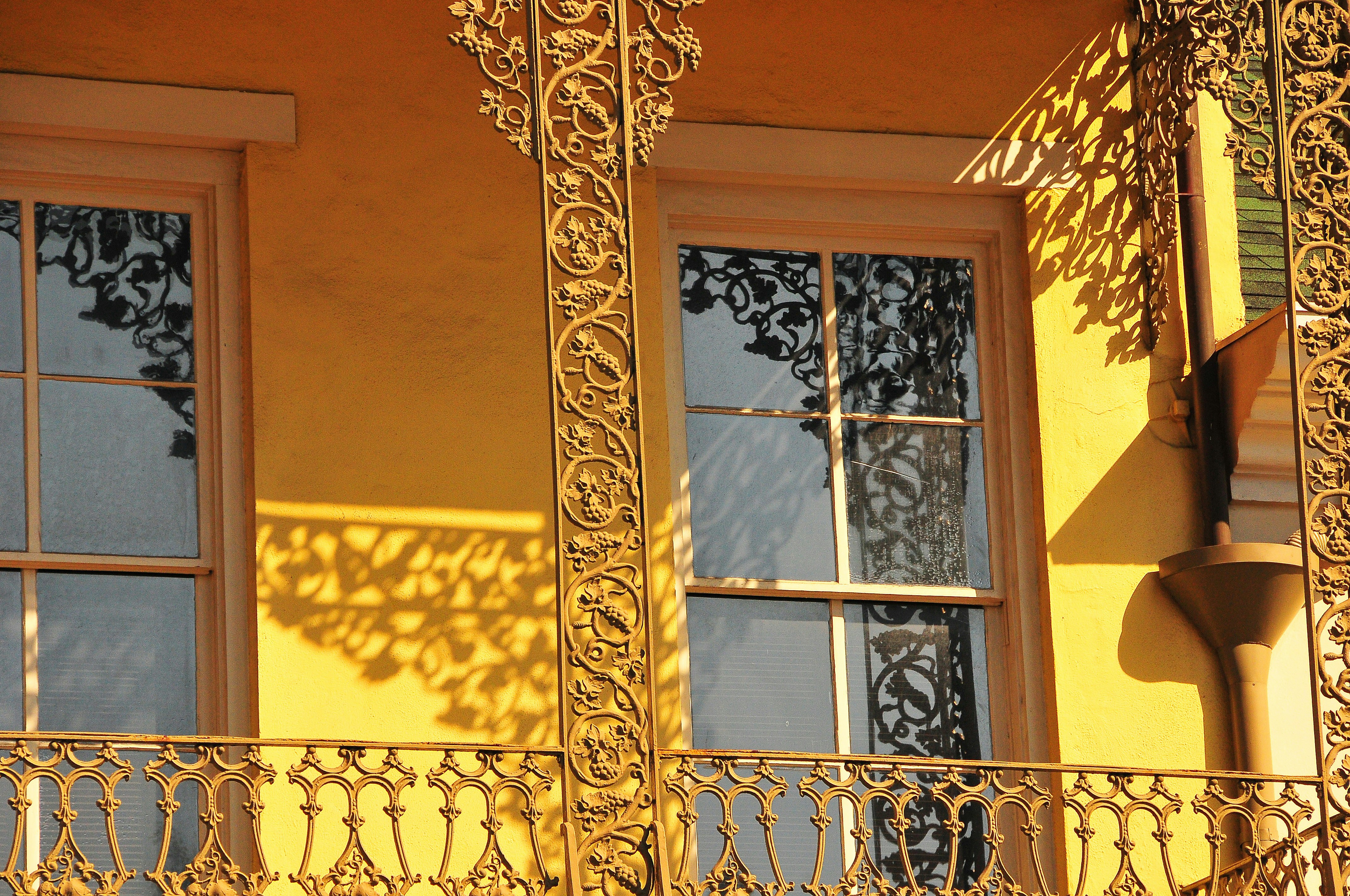 Sunlit Balcony Facade: Intricate Shadows on Warm Yellow Walls