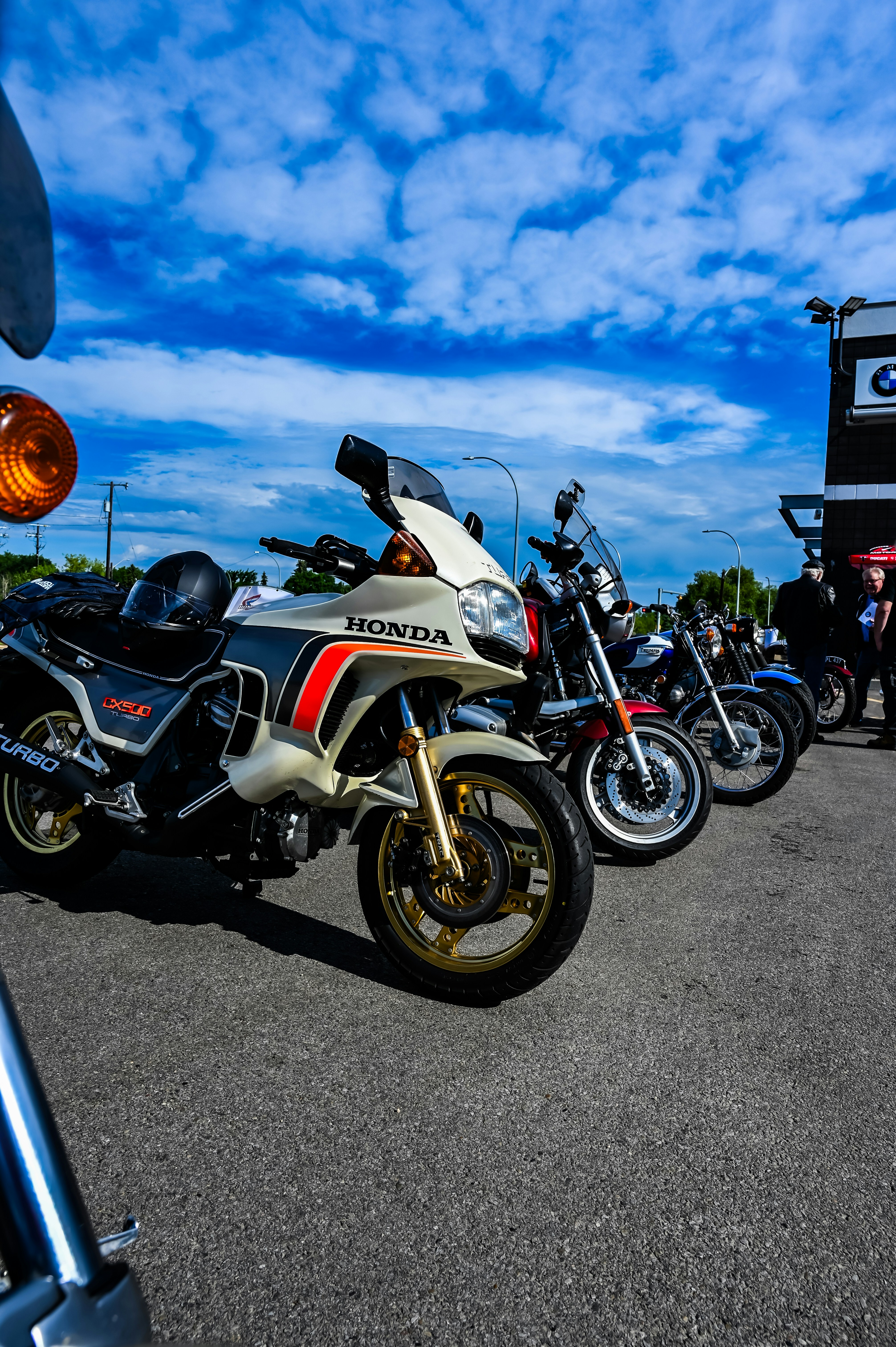 Row of Classic Motorcycles: Honda Leads the Line at a Bright Outdoor Show