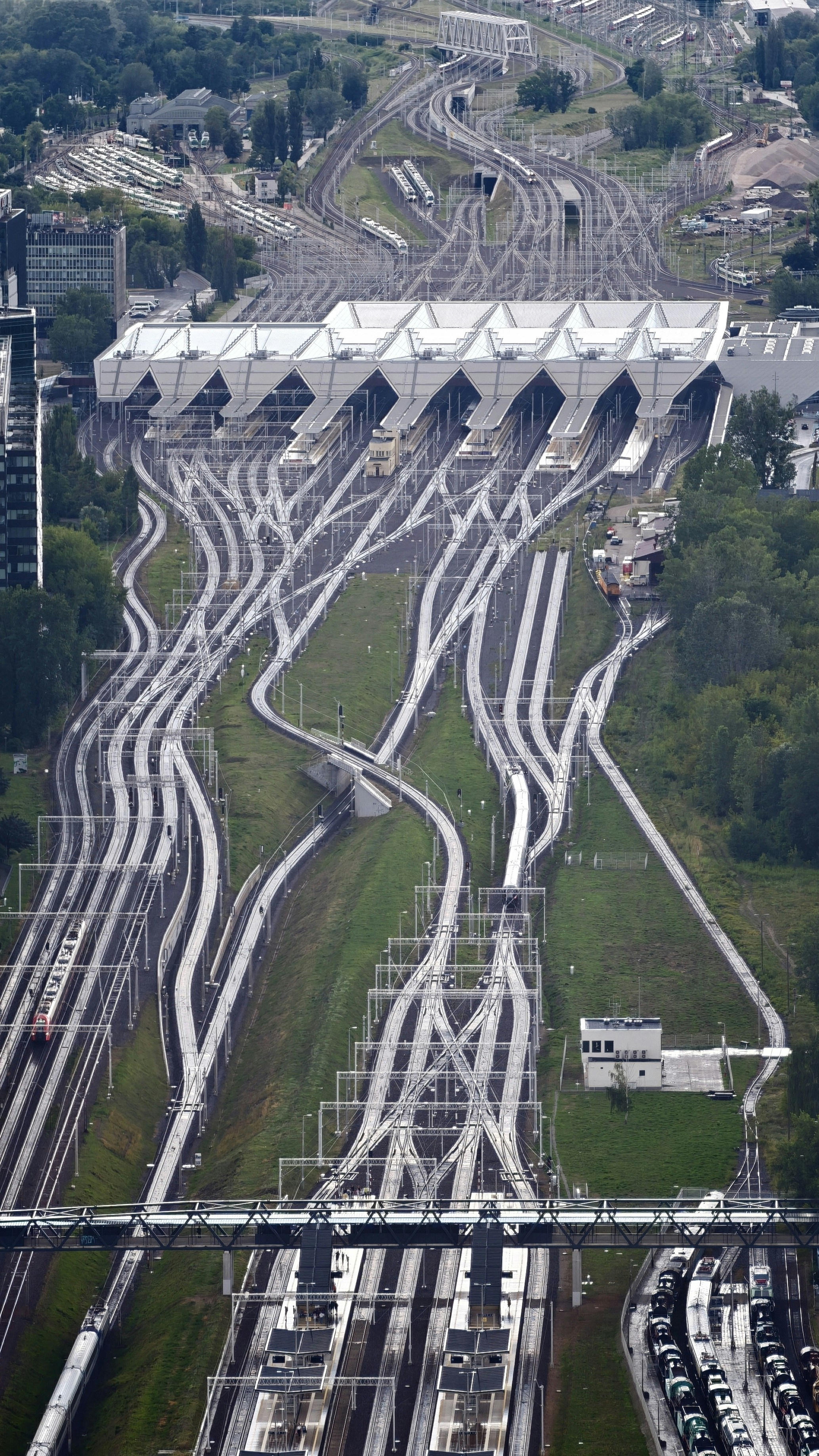 Numerous train tracks lead into a large, modern station building.