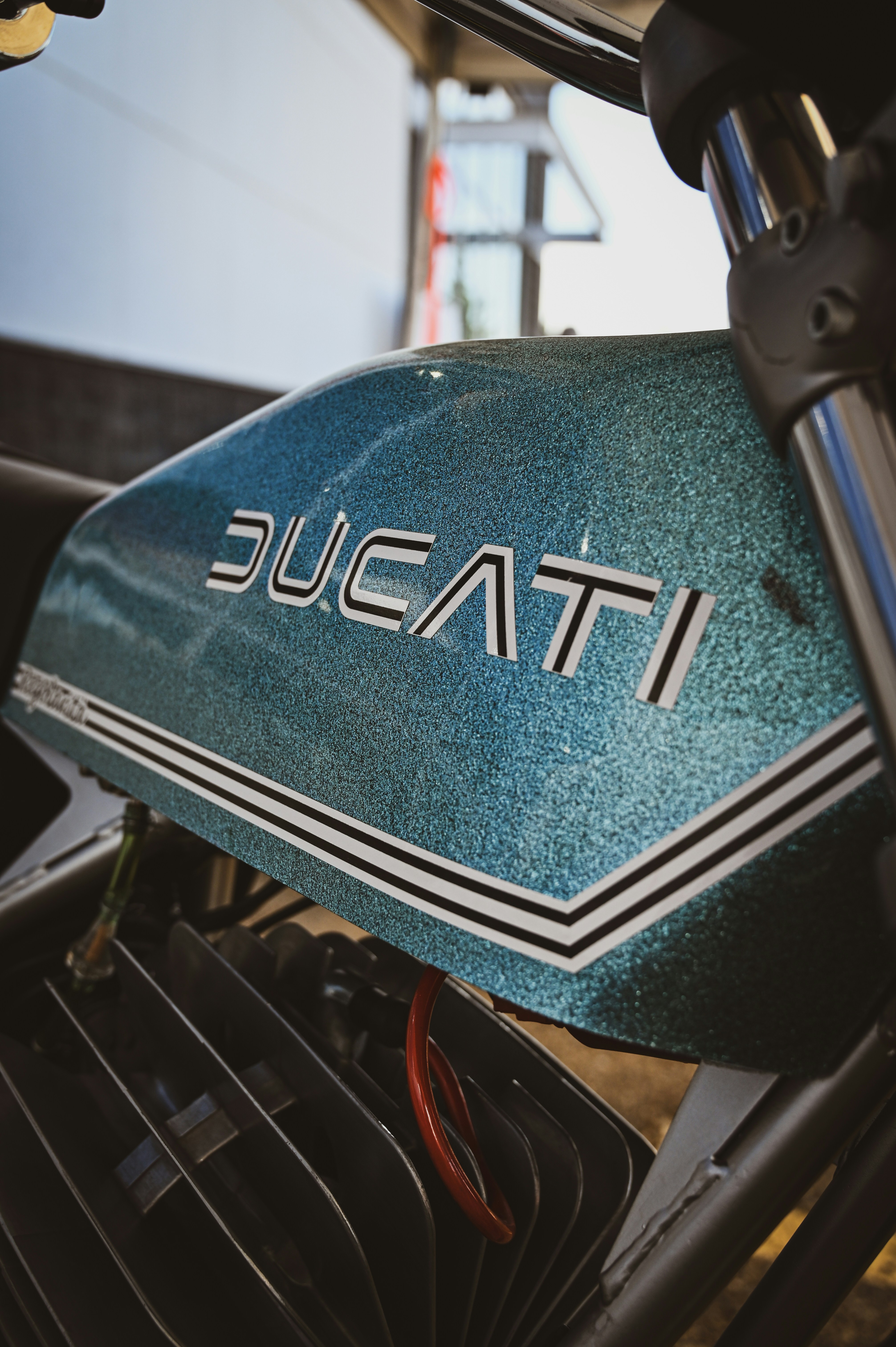 Sparkly blue ducati motorcycle fuel tank with white lettering.