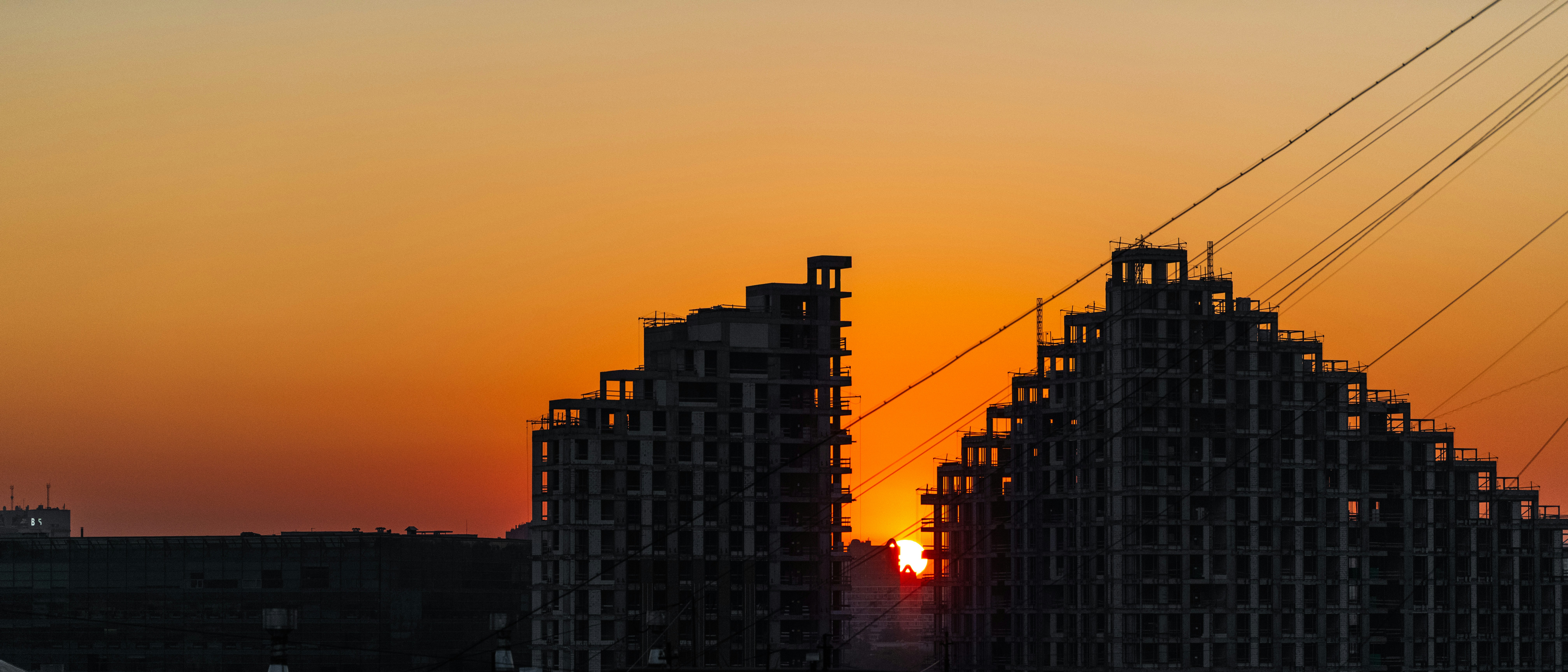 Rising Sun Between Cranes: Evening Skyline of Two Towers