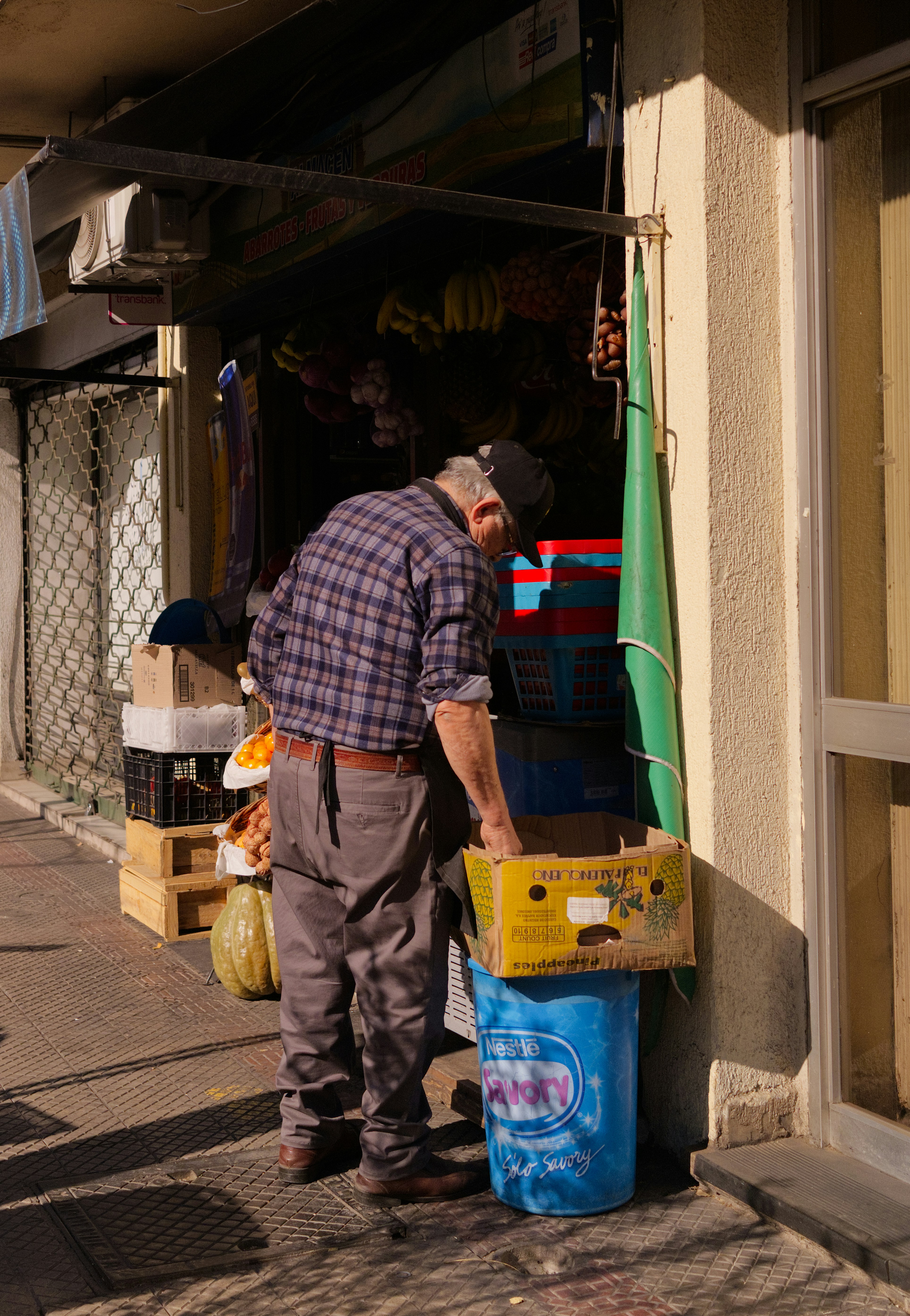 Market vendor at the curb: a man handles produce near a doorway
