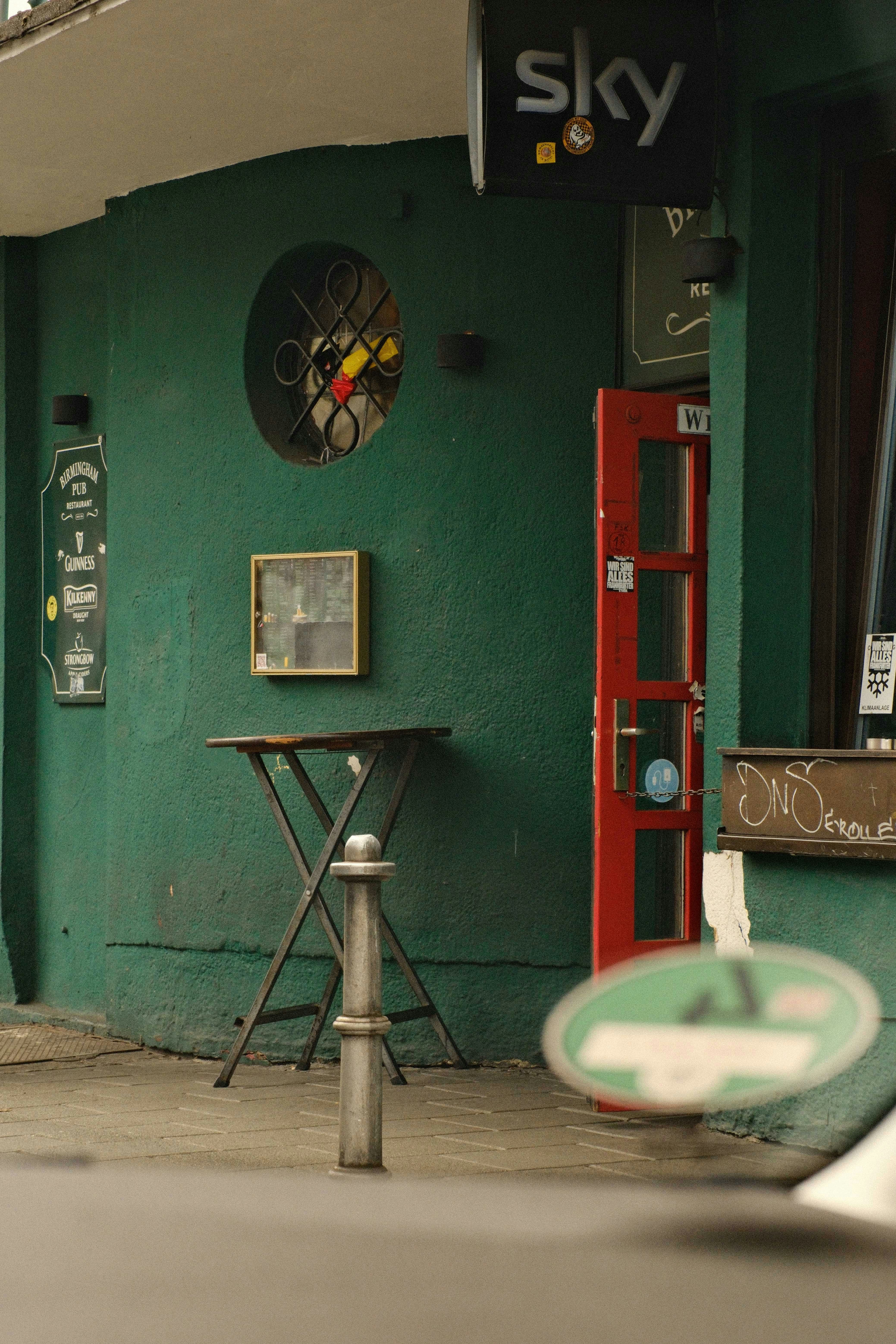 Green storefront and red telephone doorway under a Sky sign