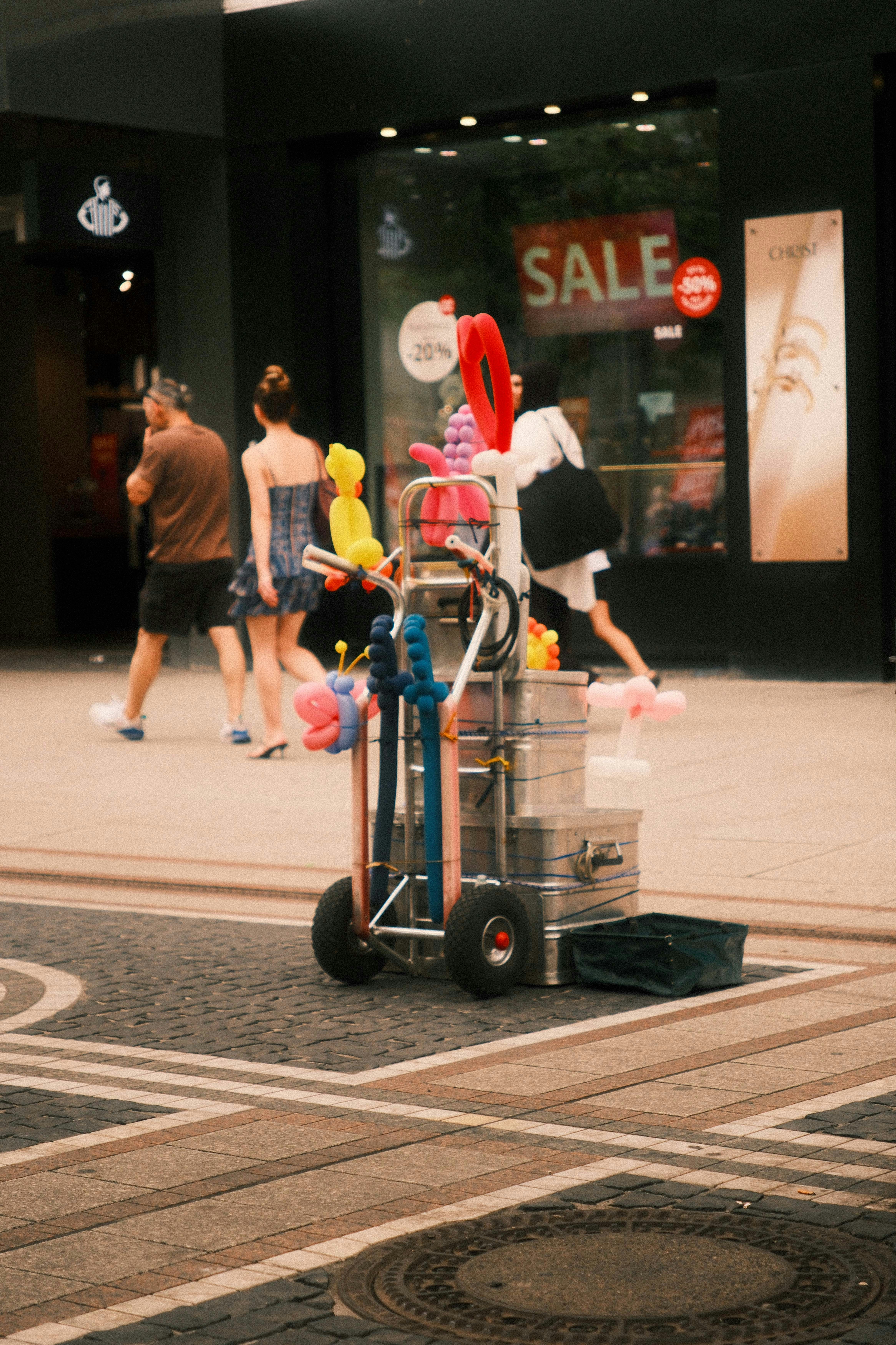 Colorful Street Cartels: Balloons on Wheels Amid Shoppers