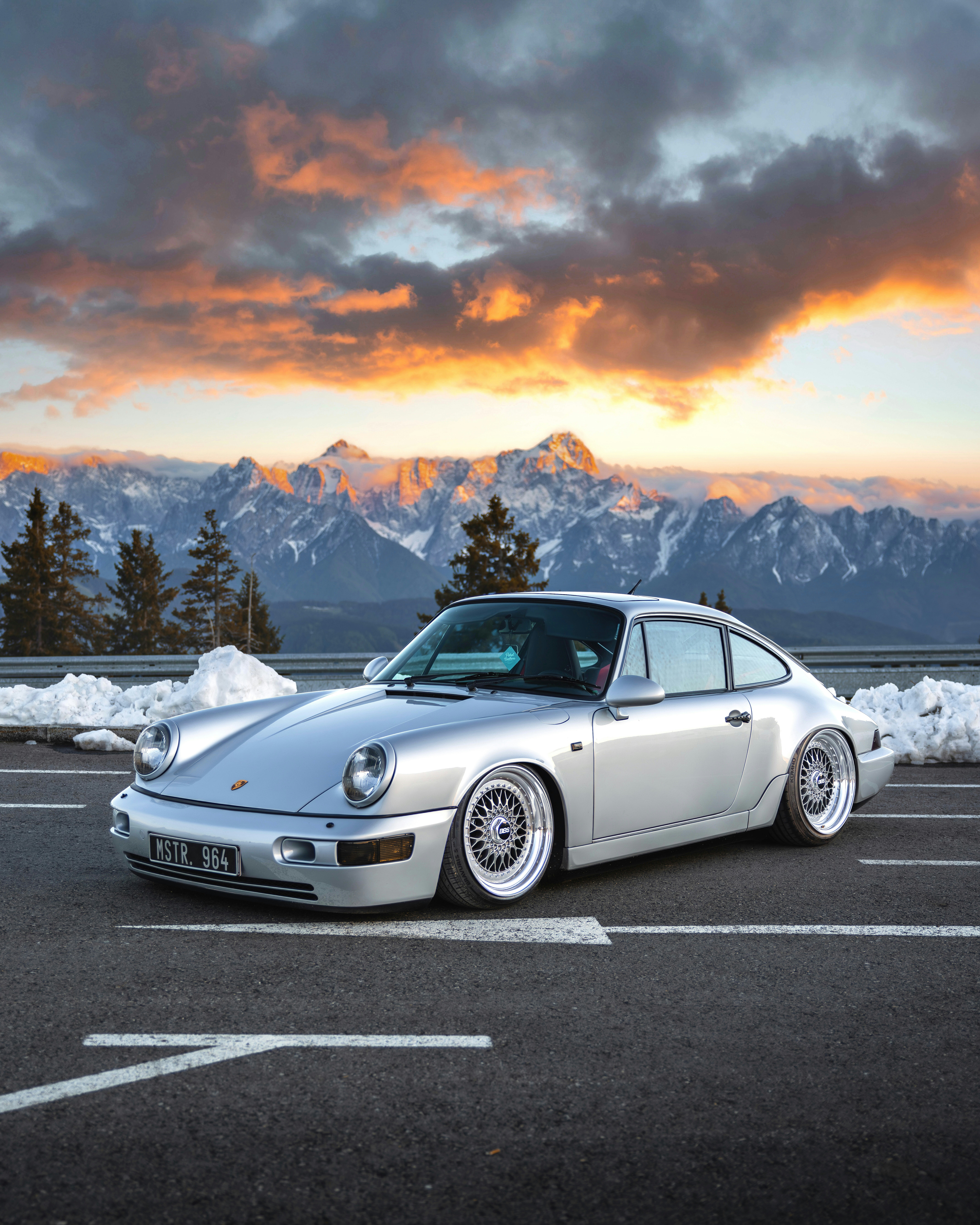 Silver Porsche Stands Boldly Against Alpine Backdrop at Dusk