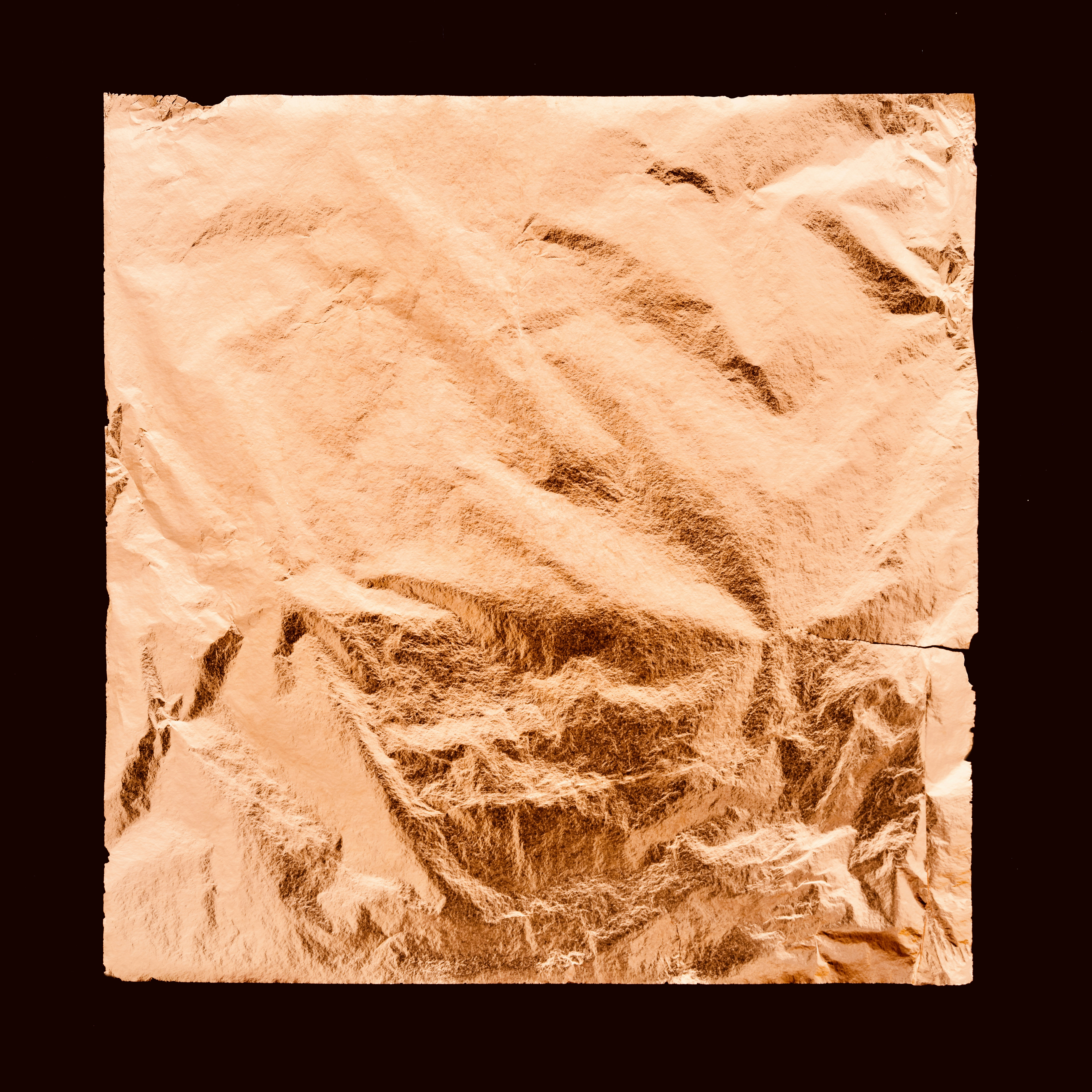 A close-up of a copper-toned crumpled sheet with soft light revealing its wrinkles and metallic sheen. The image emphasizes texture and tonal variation without identifiable subjects; note the material's surface quality and abstract form.