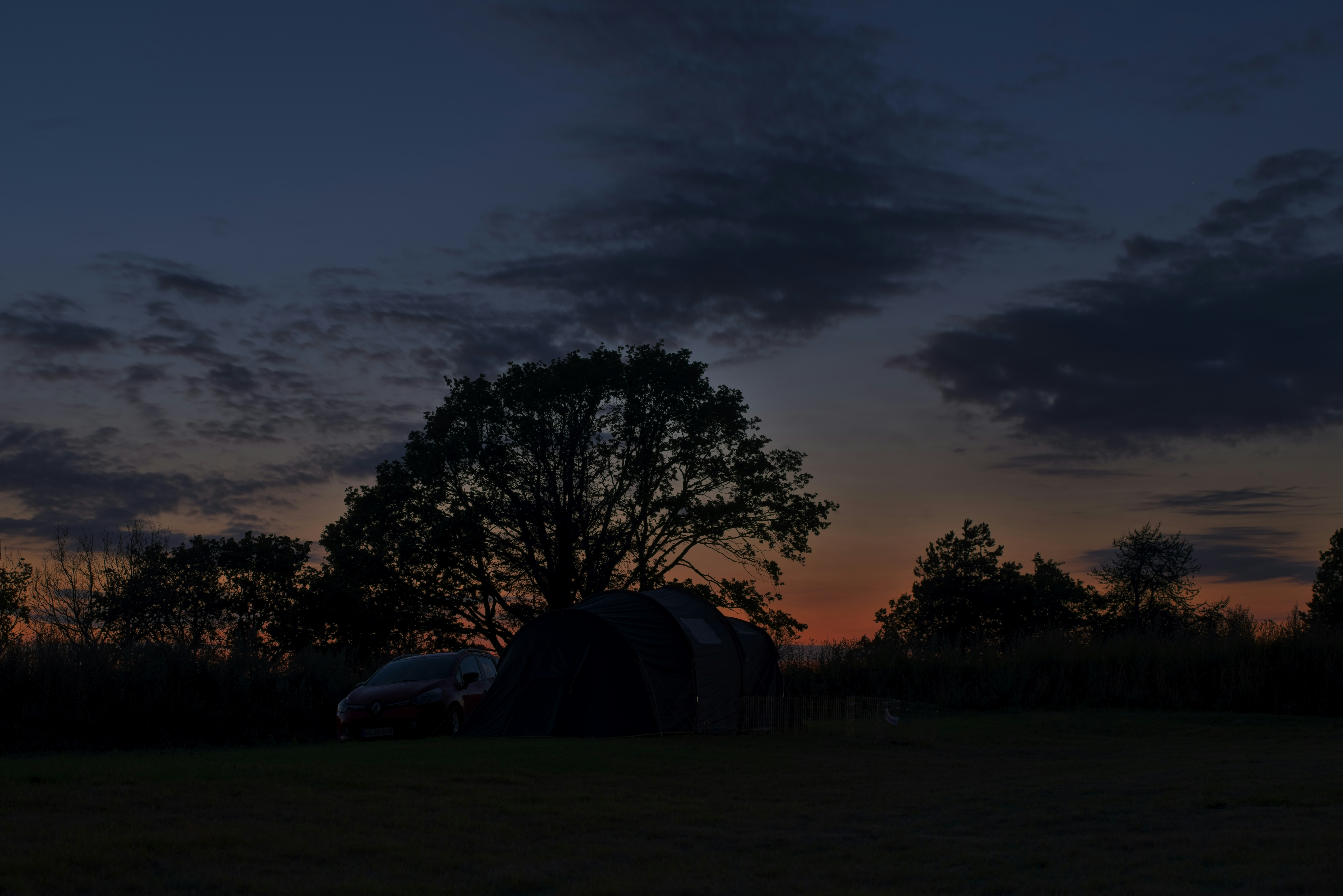 Dusk over Silent Fields: A Tent and Tree Silhouette
