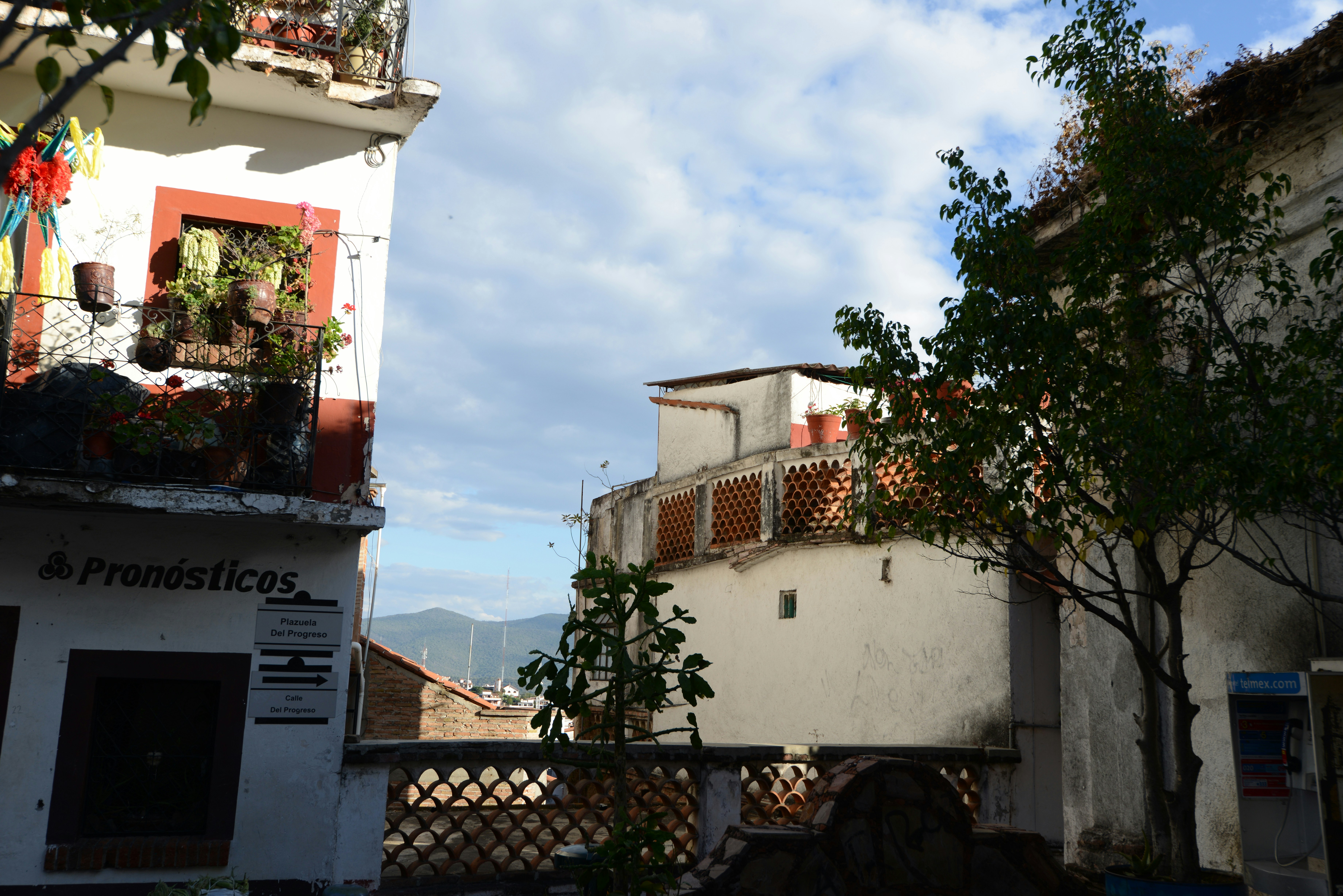 Sunlit streetscape with a whitewashed building and a balcony garden