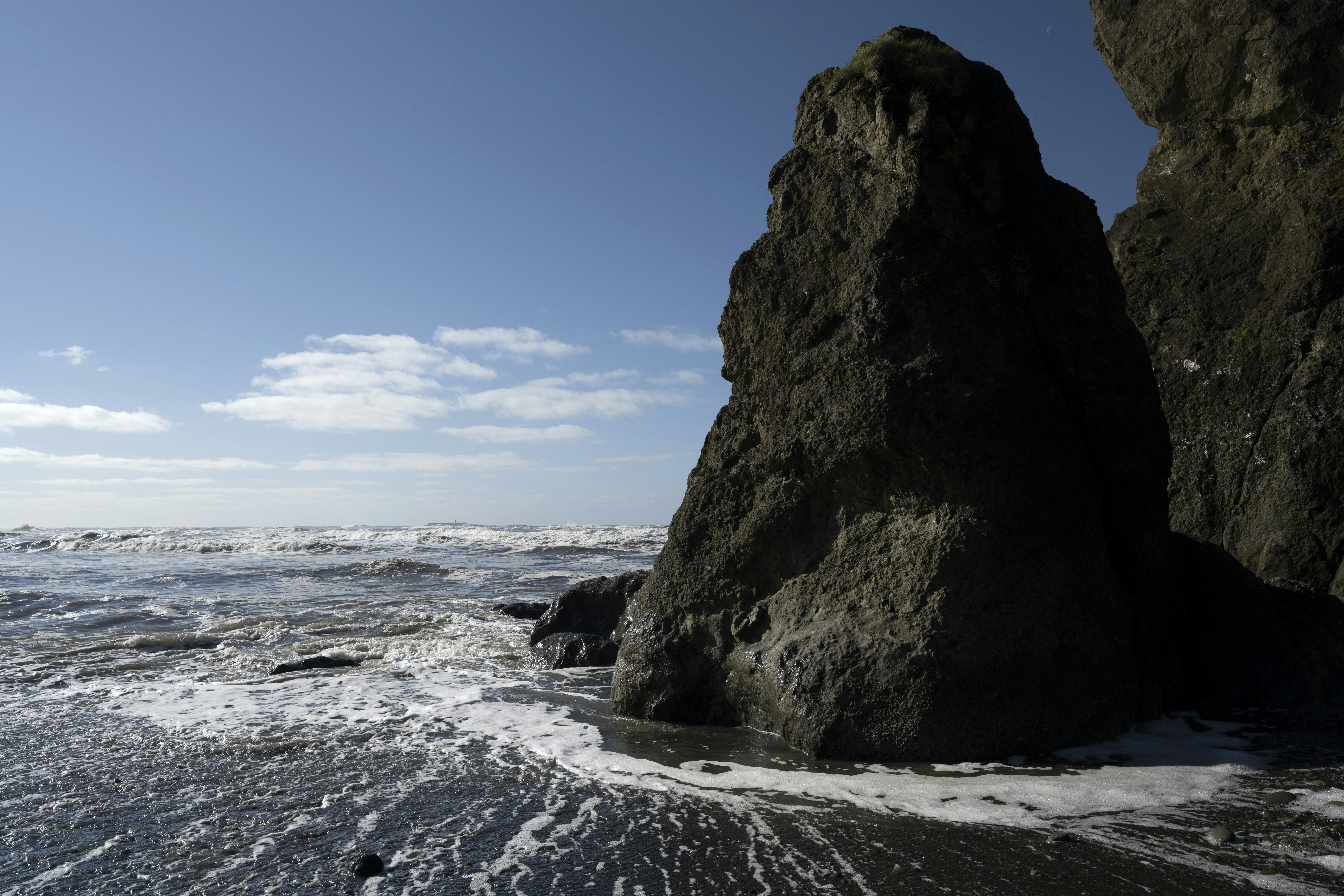 Coastal Sentinel: A rugged rock against the surf at dusk