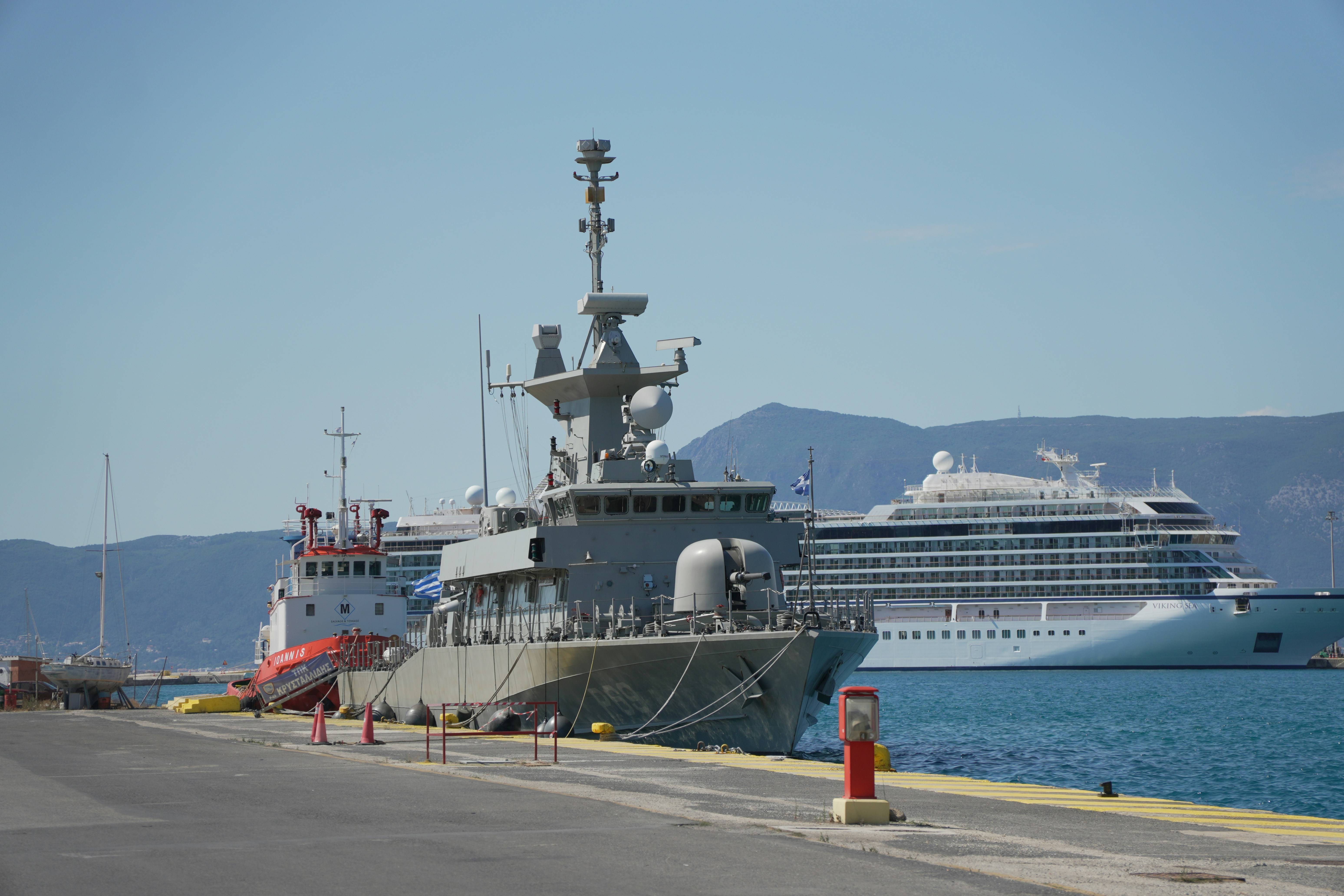 Harbor Sentinel: A Warship Docked Beneath Cruise Veils