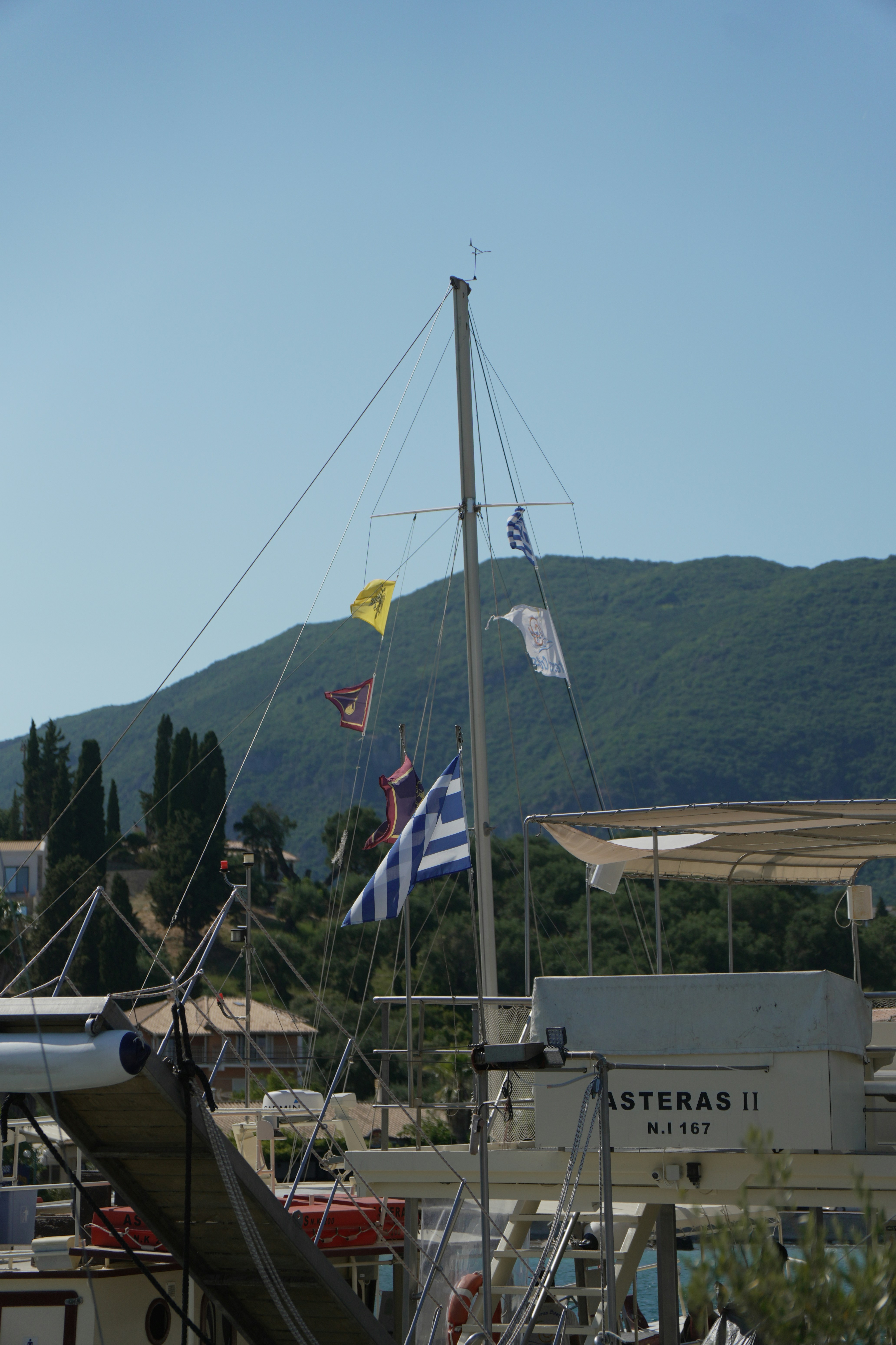 Sailing Rig and Flags Against a Quiet Coastal Mountain Backdrop