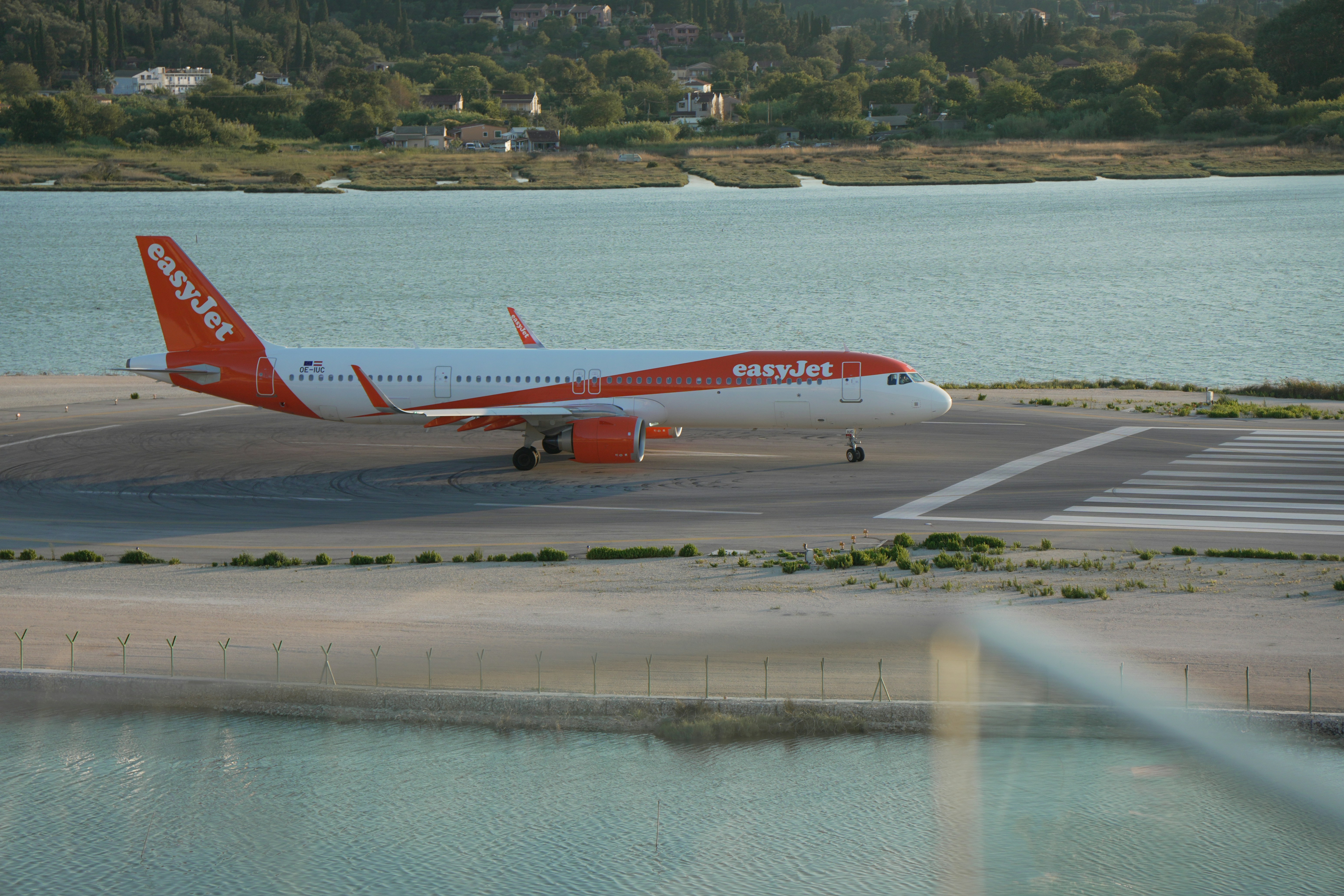 Orange EasyJet Jet on a Quiet Airport Tarmac by a Calm Water Body