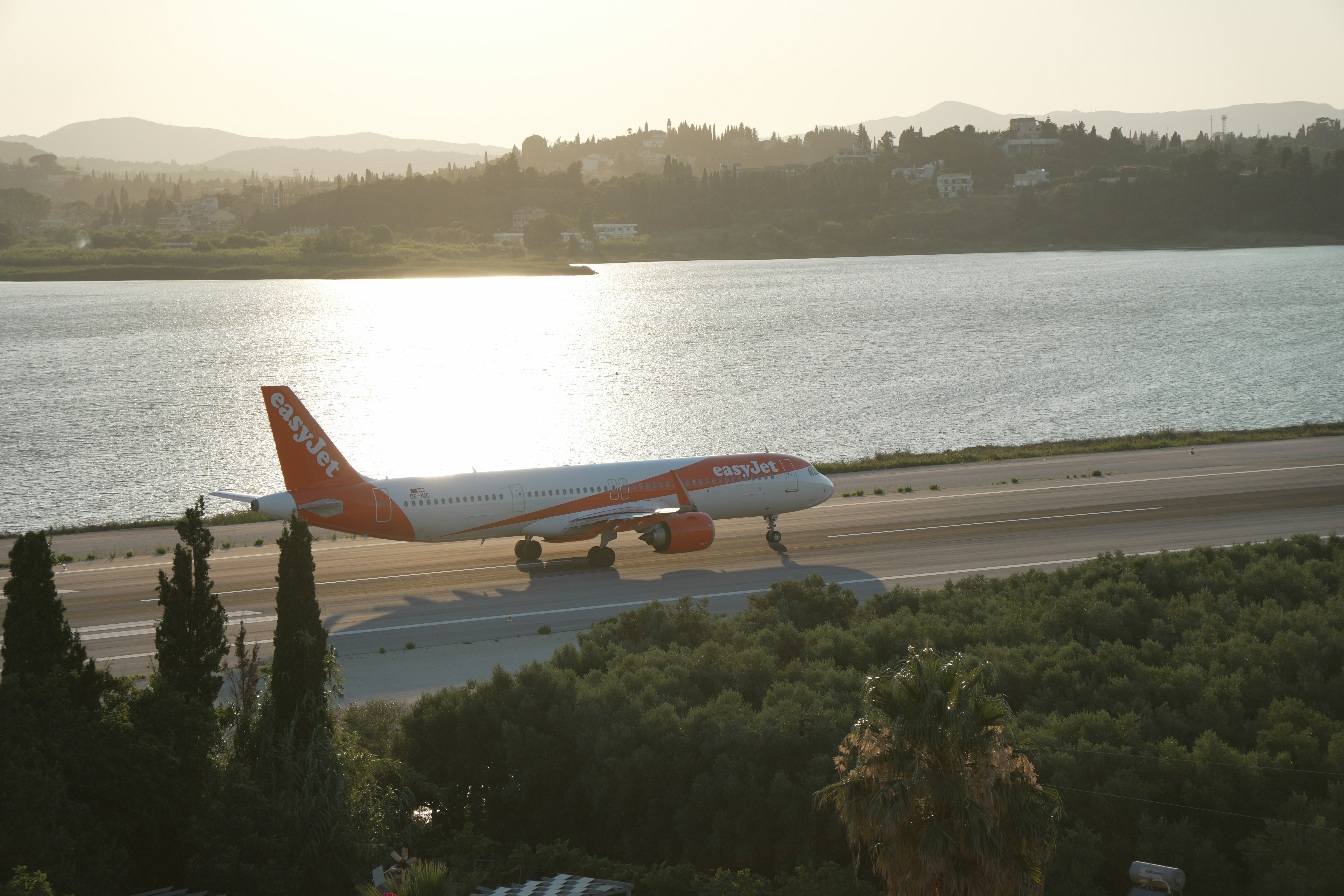 Orange-Striped airliner gliding along a sunlit runway at dusk