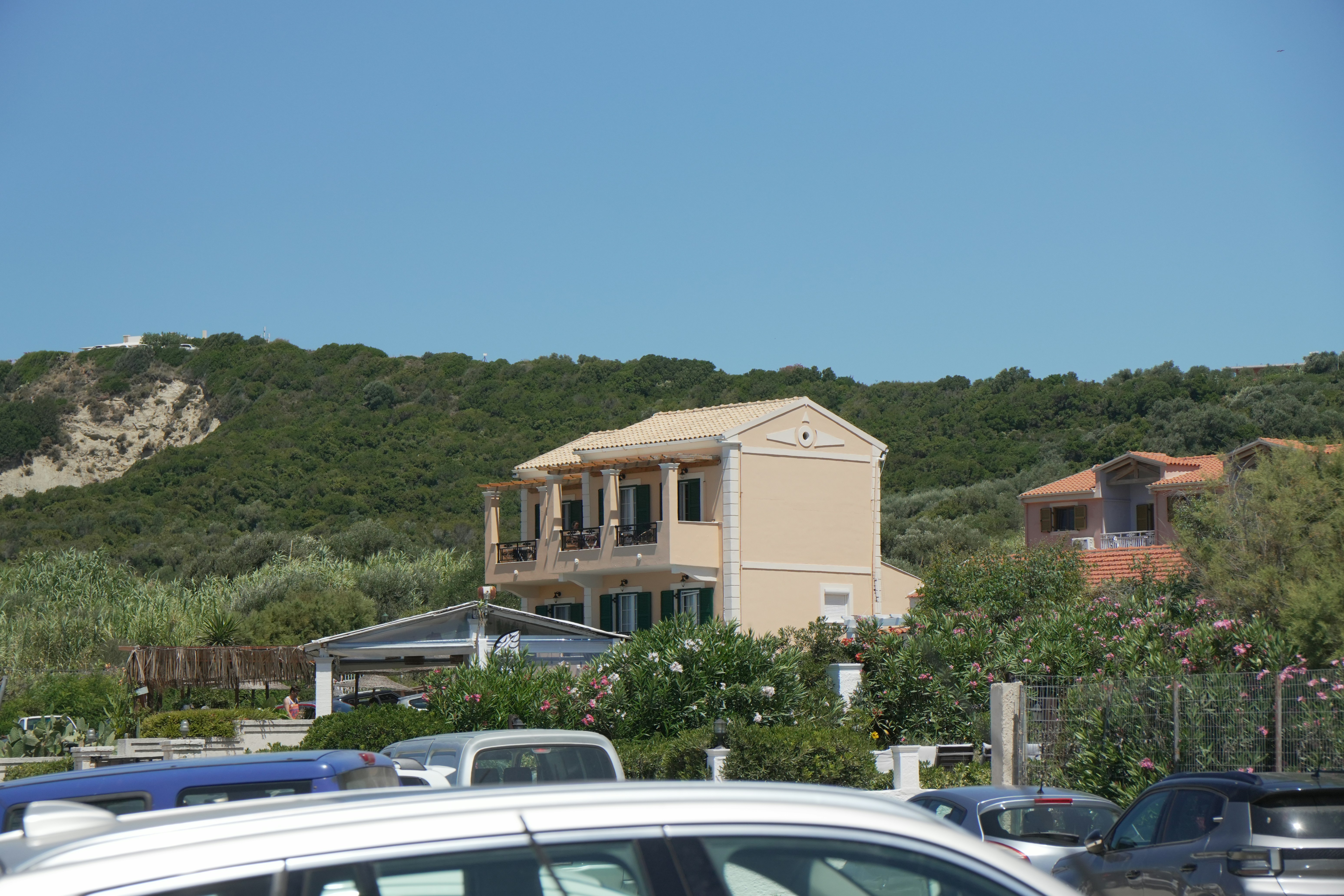 Coastal Terrace: A Beige Villa Overlooking a Car-Filled Cove