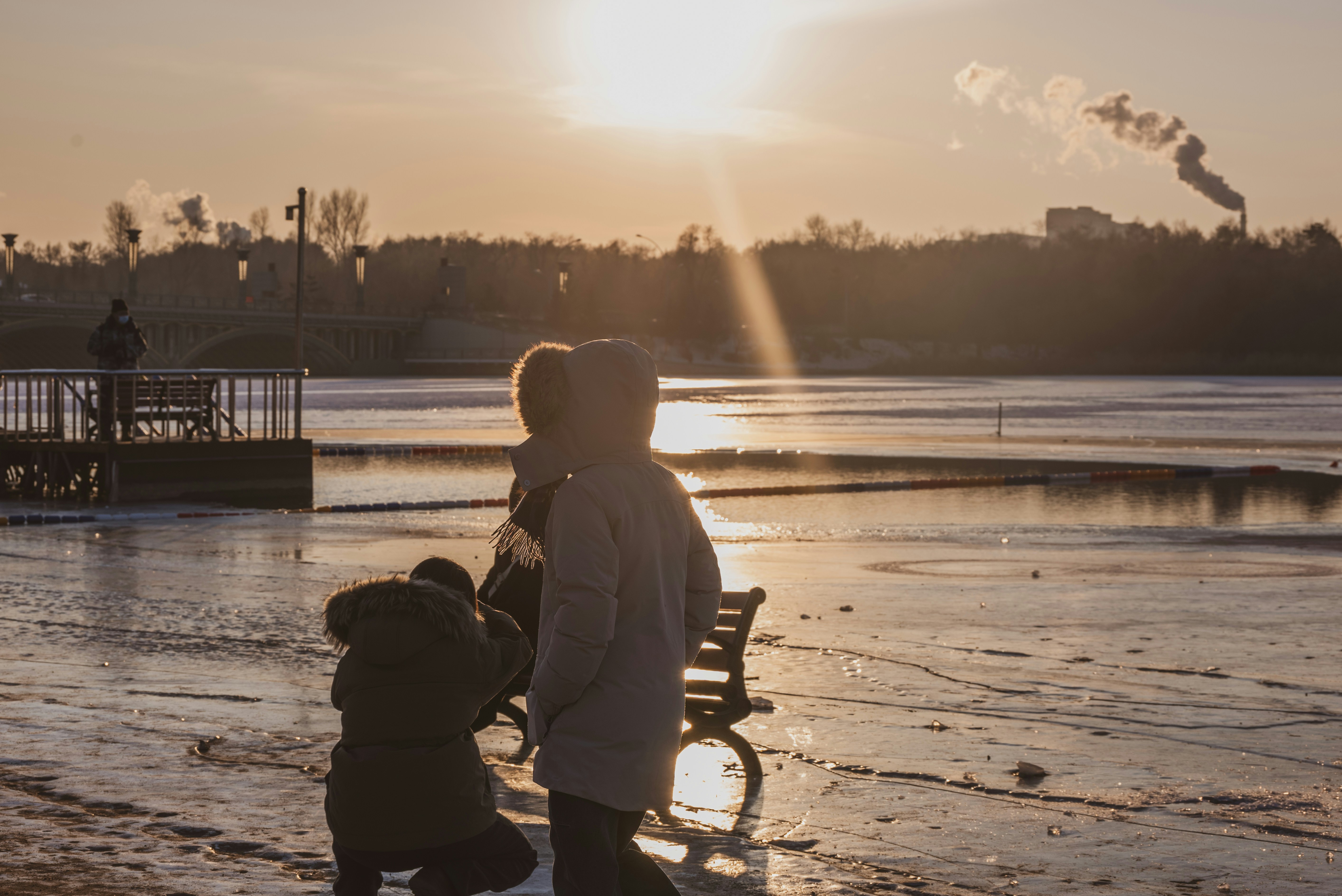 Warm Silhouette of a Family in a Sunlit Park by the Frozen Pond
