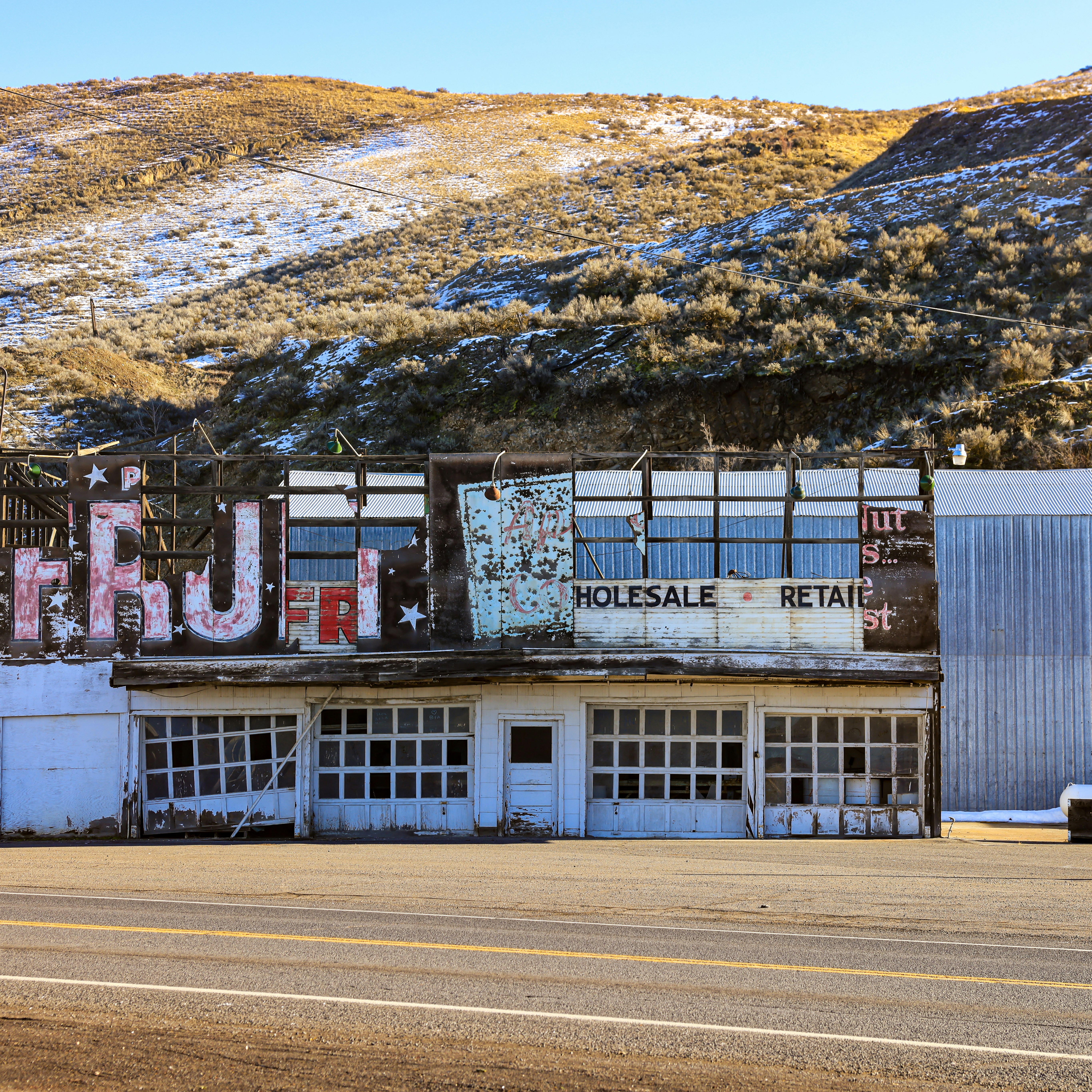 Weathered storefront beneath a sunlit hillside