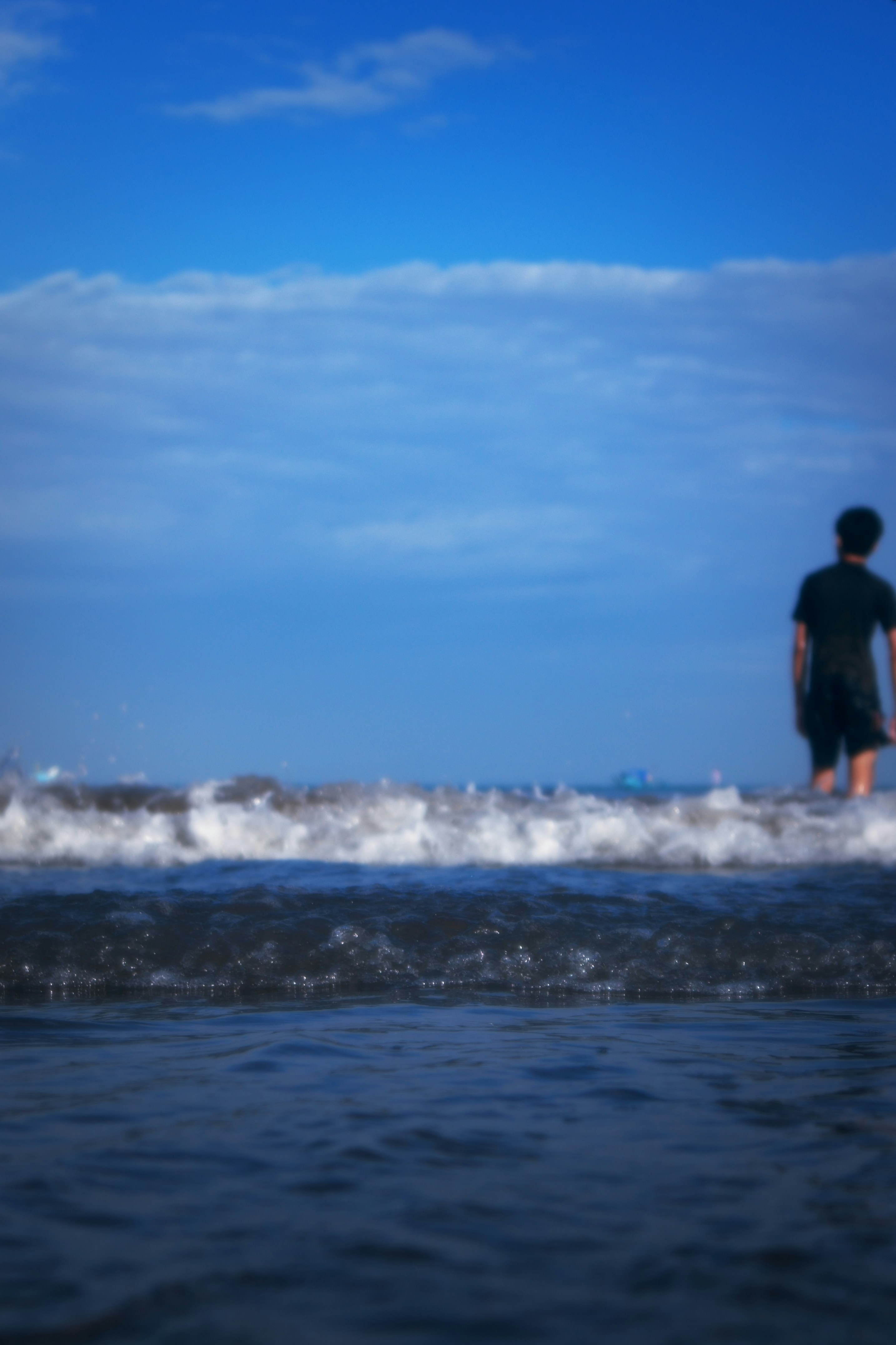 Beyond the Crest: A Lone Surfer at Distant Shore
