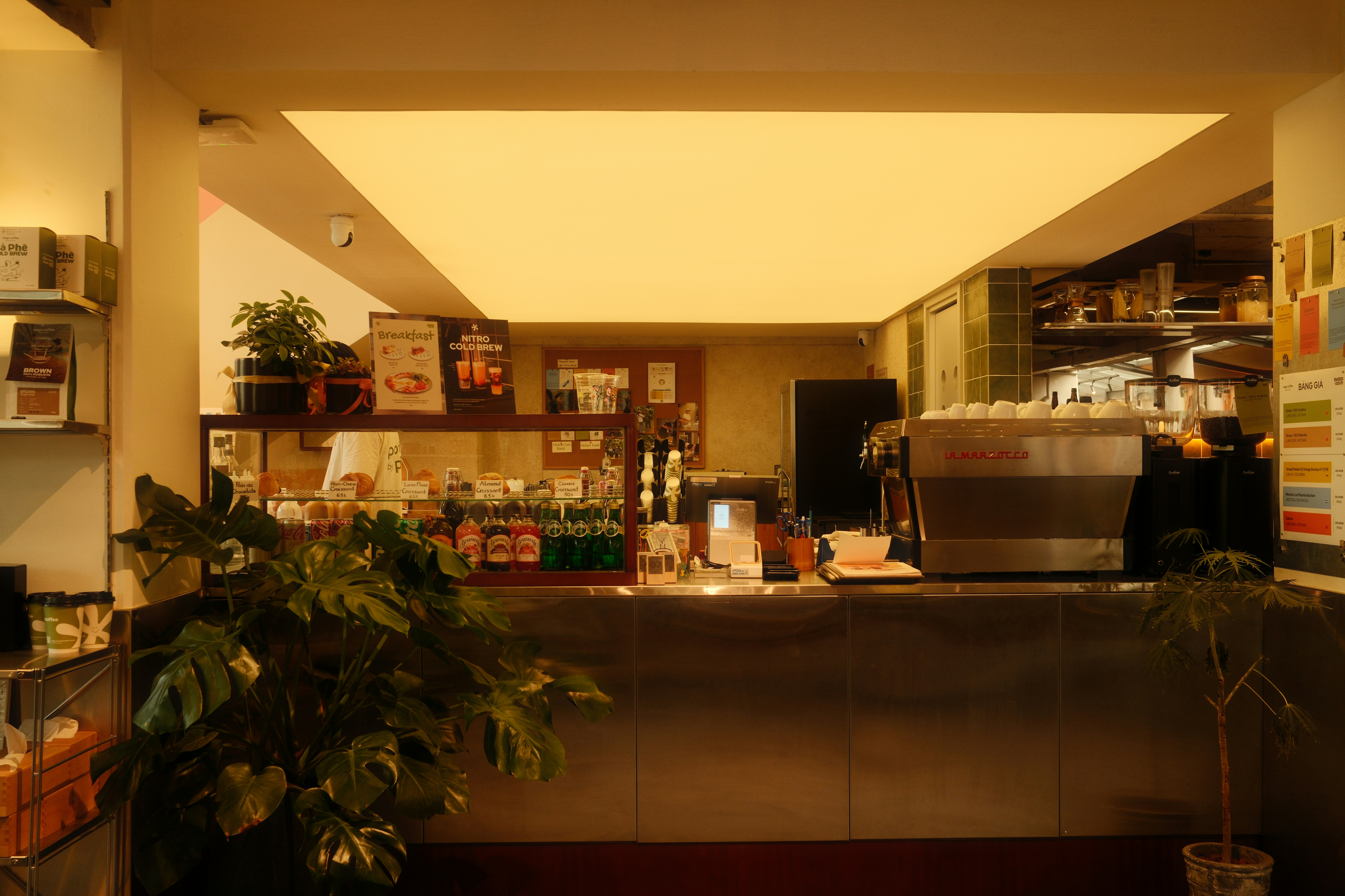Warm Café Interior with Milk-White Lighting and Stainless Counter