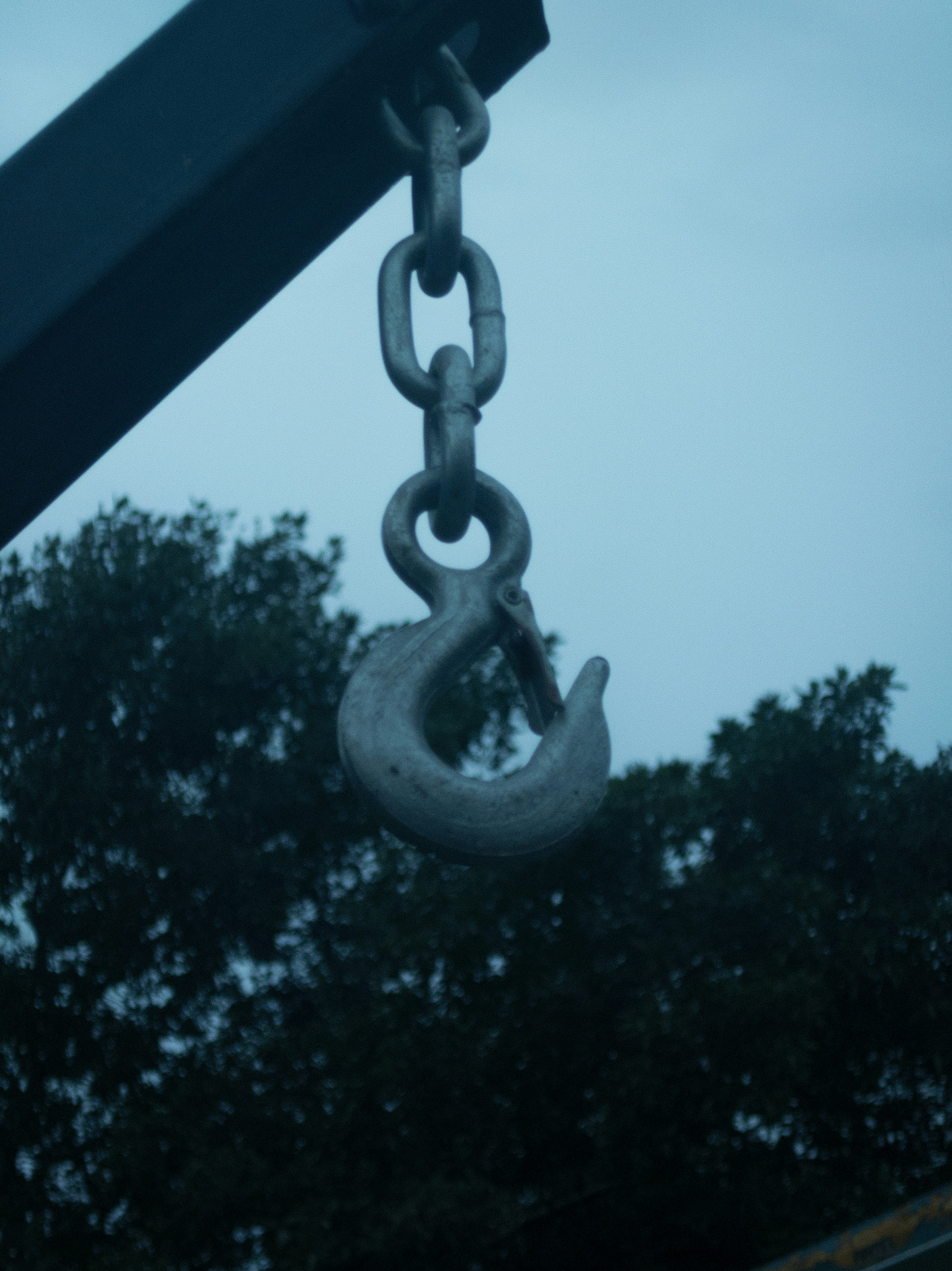 Crane Hook in Focus: Weathered Steel Against Twilight Sky