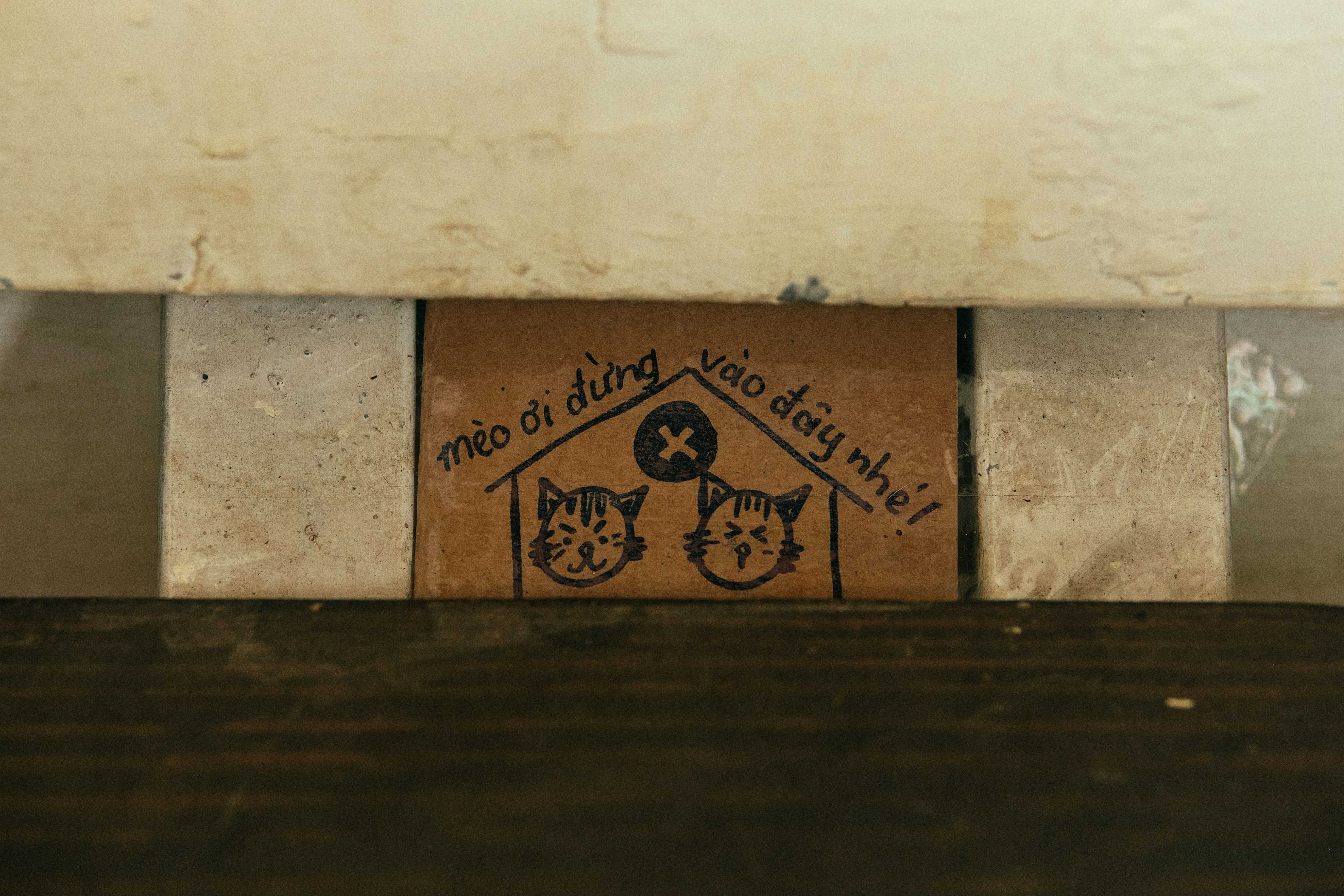 Two ceramic tiles with a playful cat drawing beneath a stair ledge