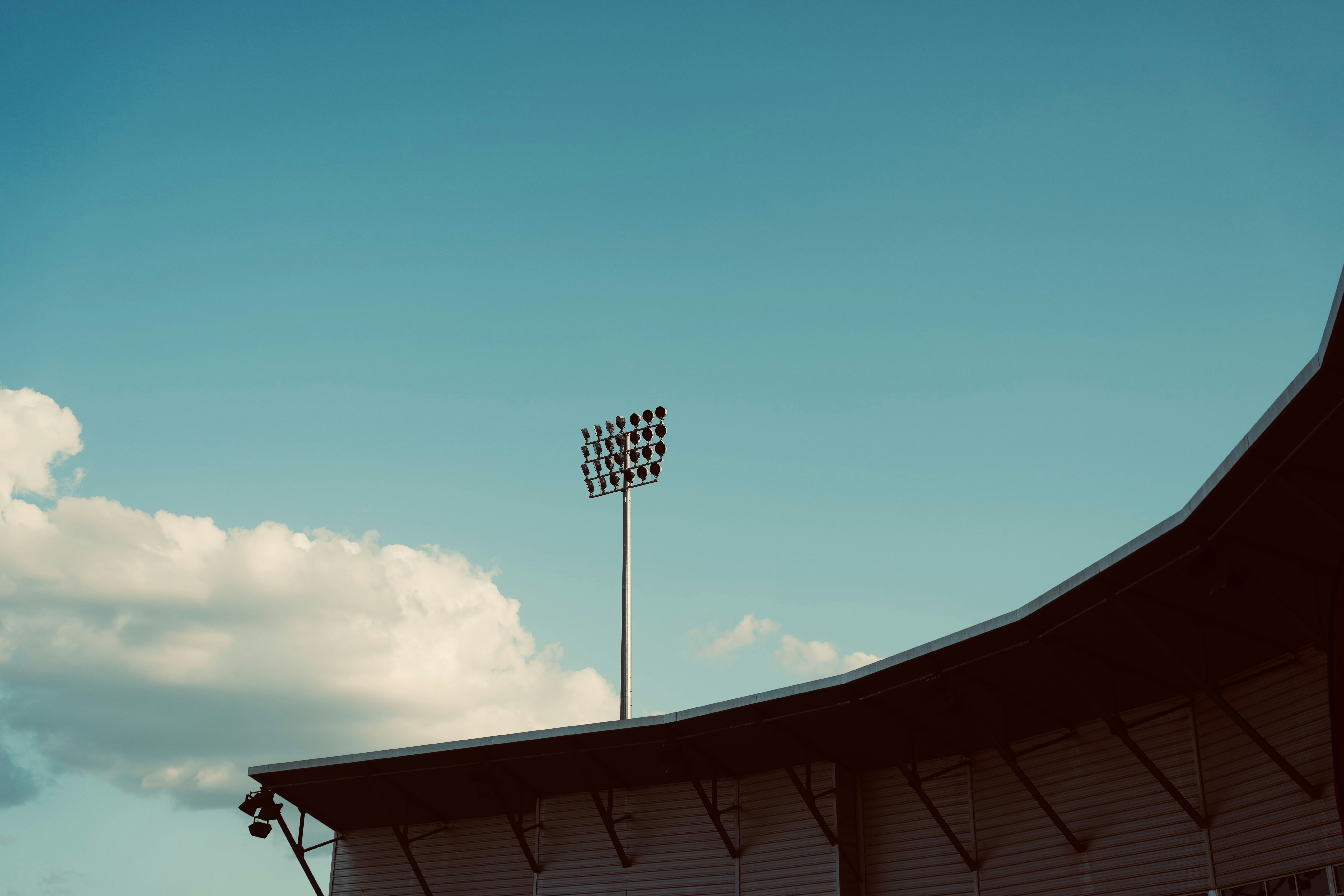 Blue Sky Over a Stadium Roof: Minimalist Edge and Light Tower