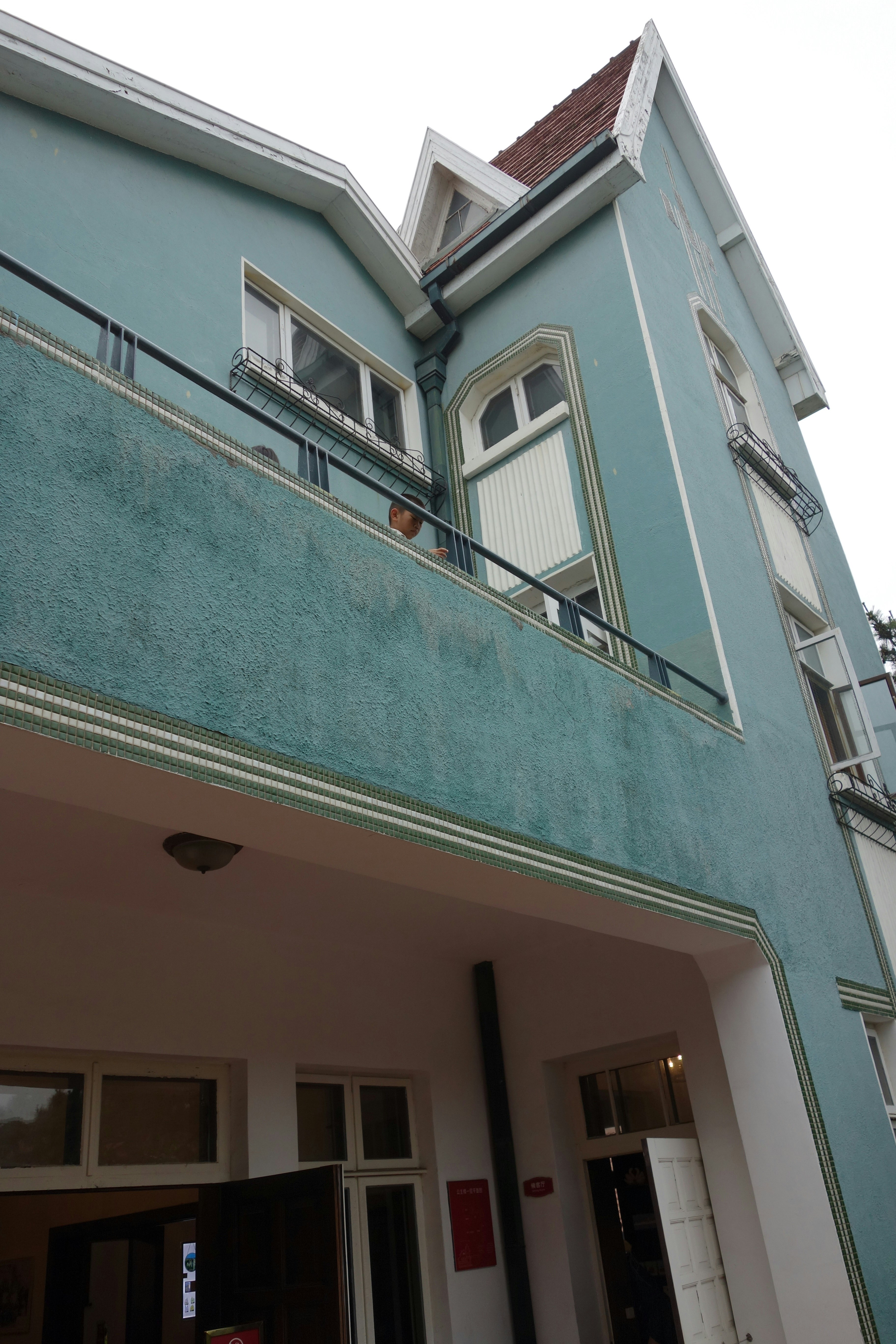 Teal Facade: A Quiet Balcony Moment on a Sunlit Street