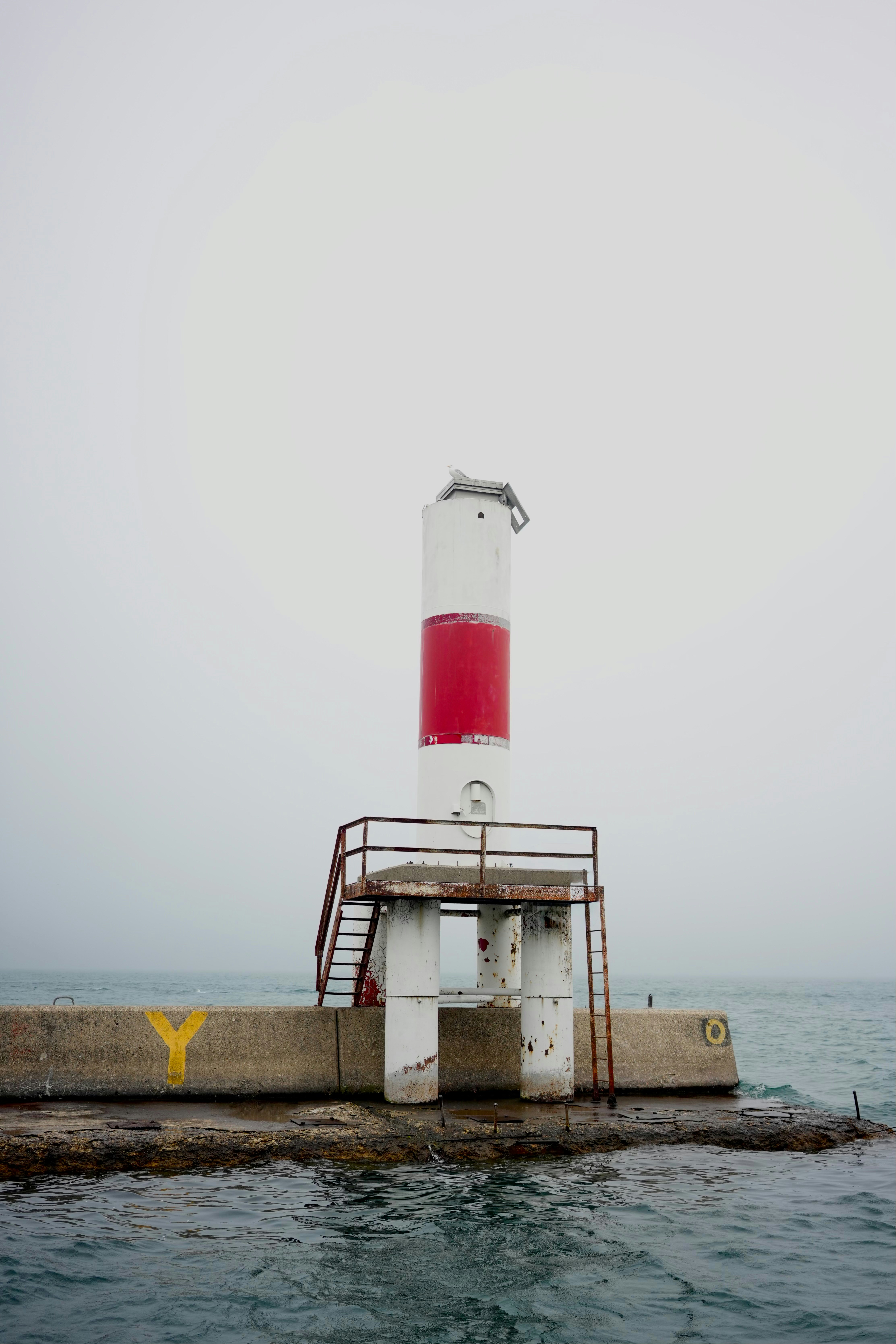 Lighthouse on a Quiet Jetty Peering Over a Calm Sea